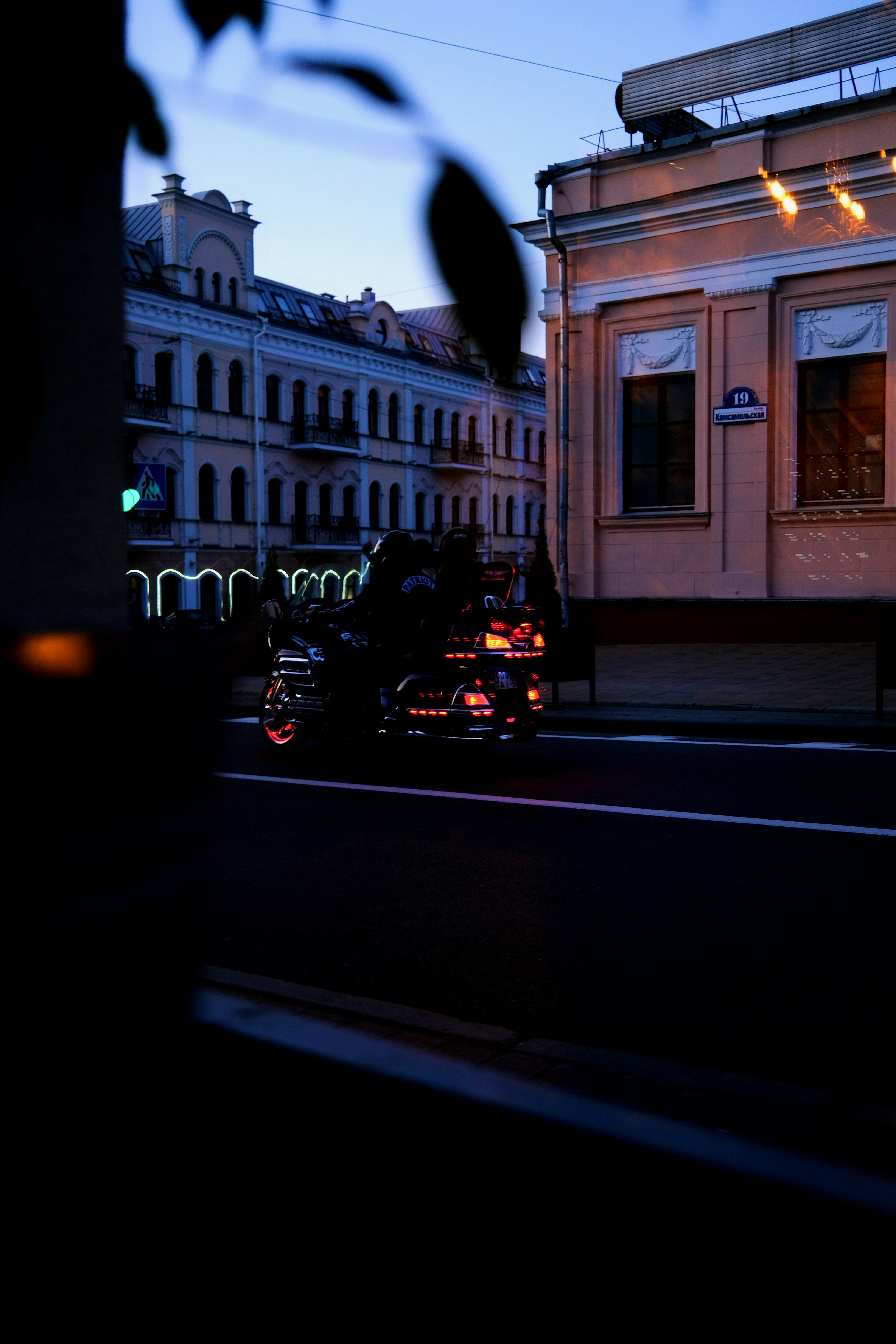 Blue Hour Ride: Neon Tail Lights Against Historic Facades
