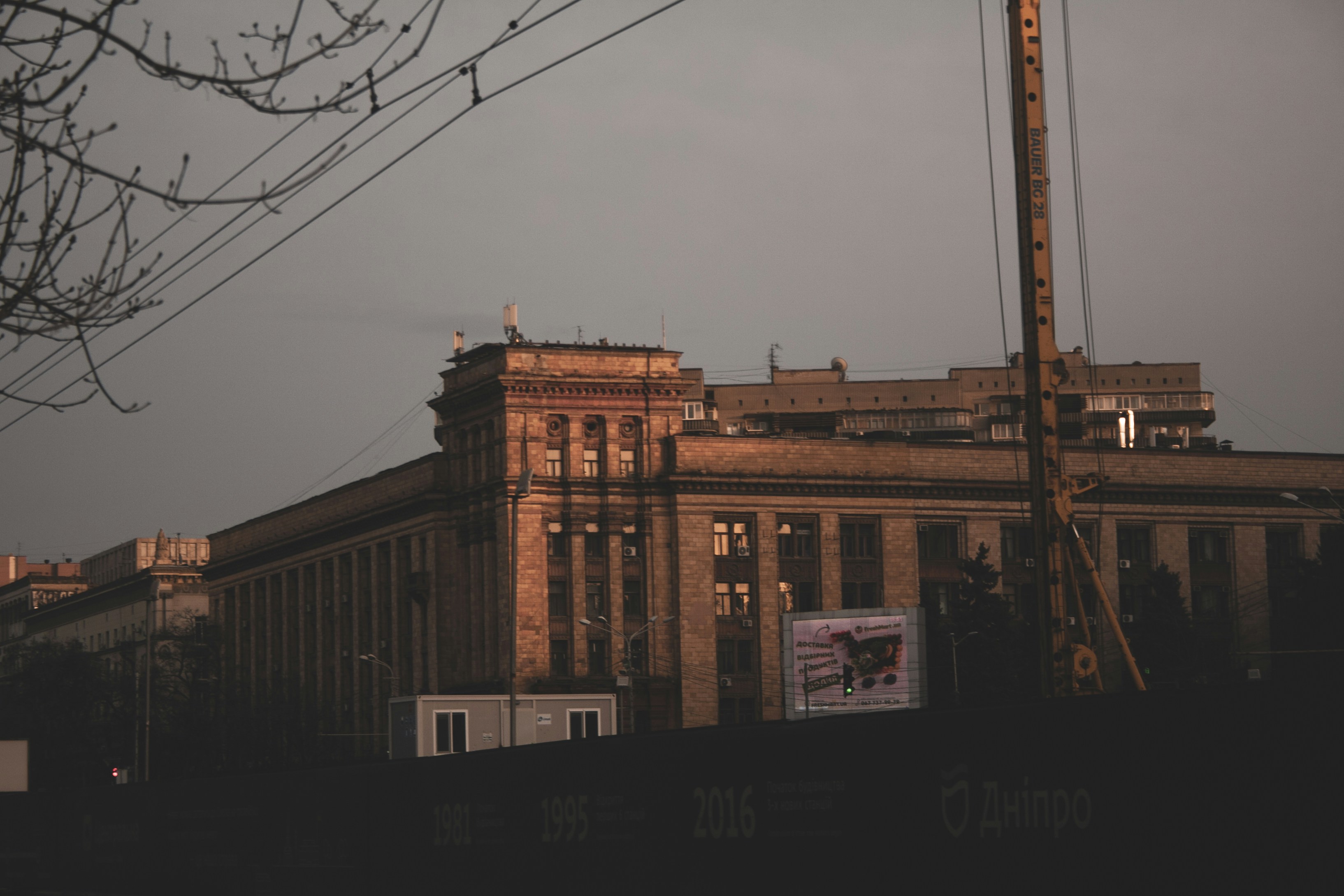 Dusk-lit Bricks: Warm Light Bathes a Historic Block Beneath a Construction Crane