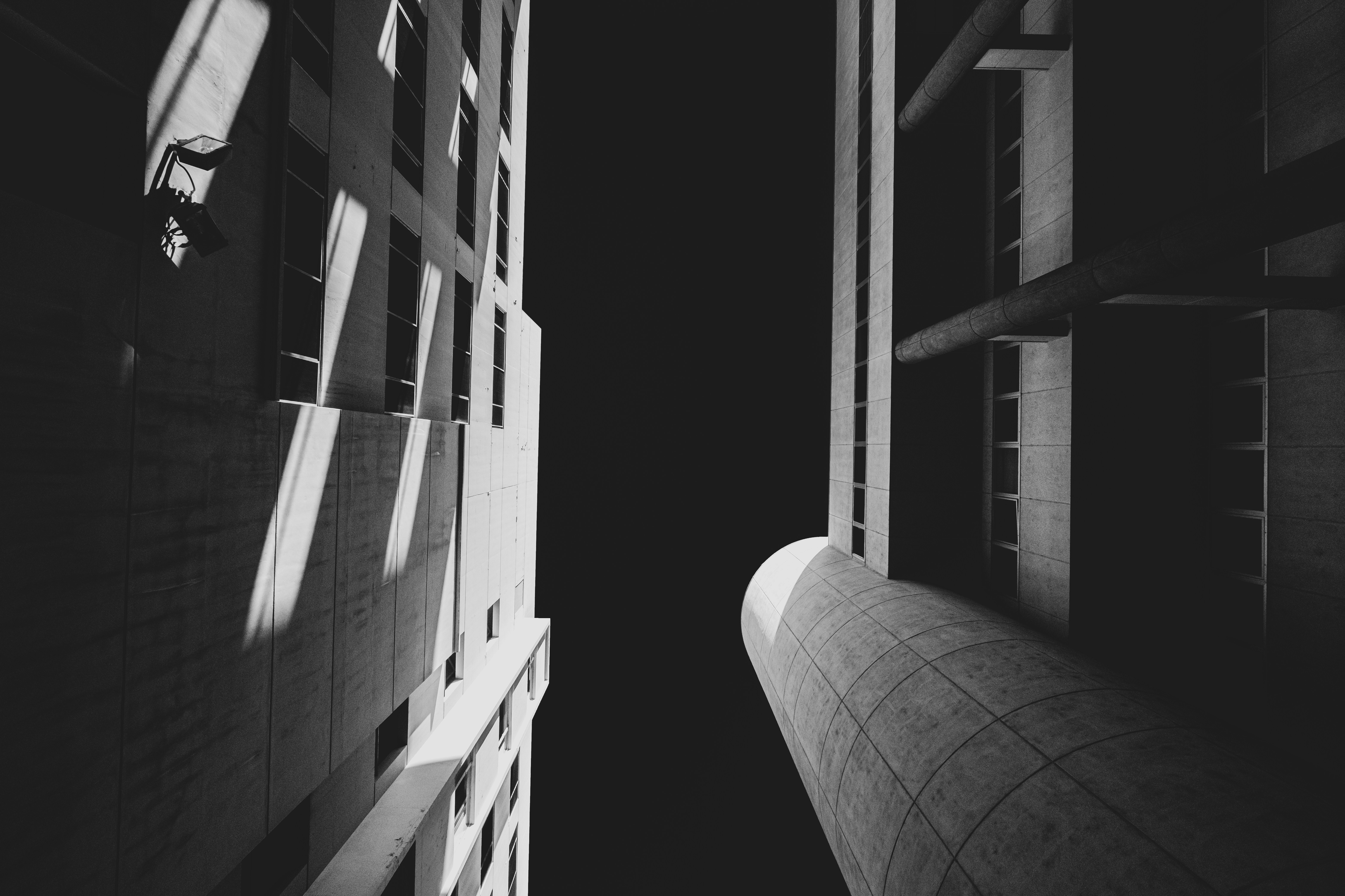 Abstract architectural composition showcasing stark concrete structures and dramatic shadows. The upward view emphasizes the interplay of light and form.