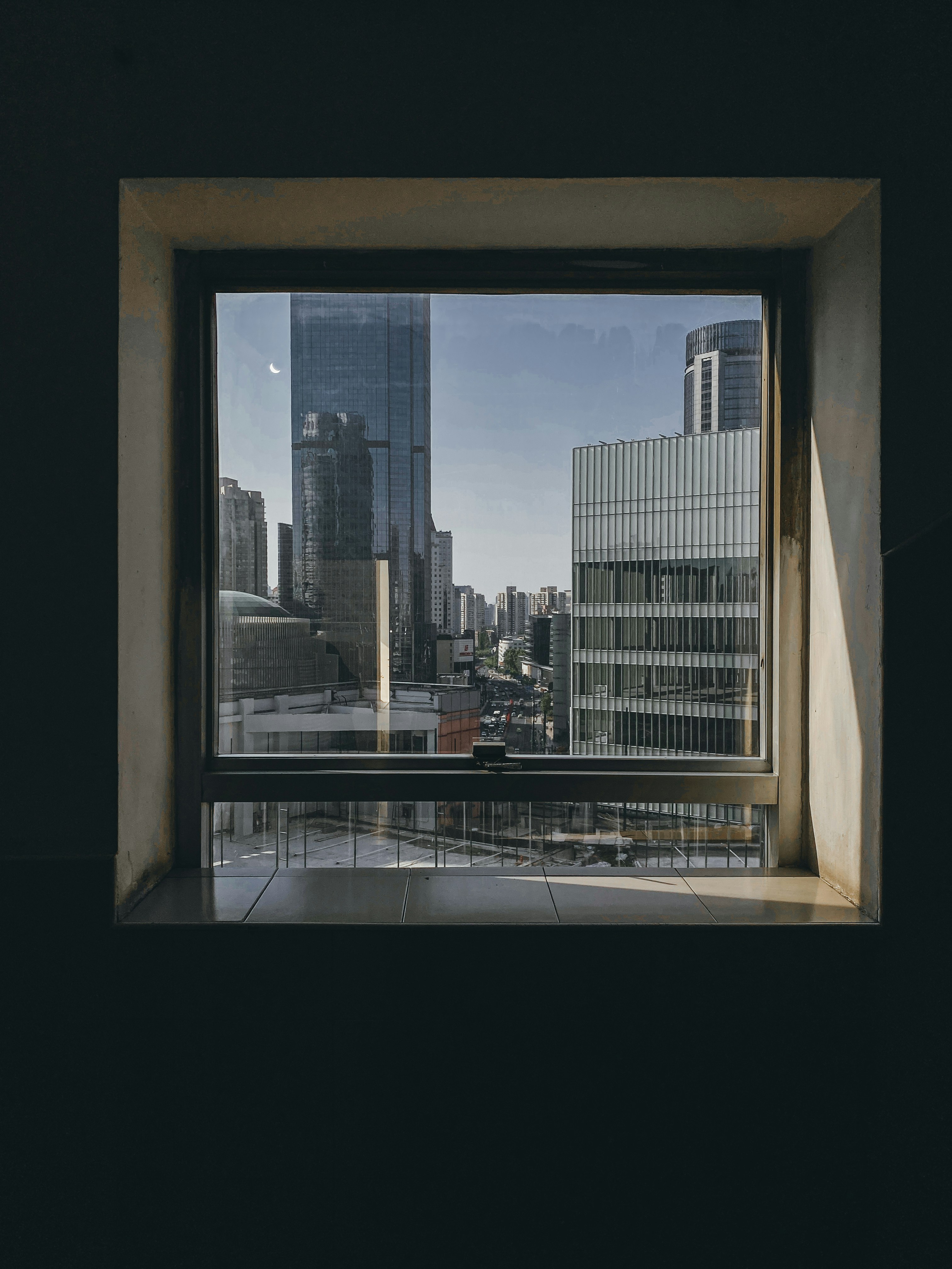 View of a bustling cityscape through a modern window frame, showcasing a blend of architectural styles and urban life.
