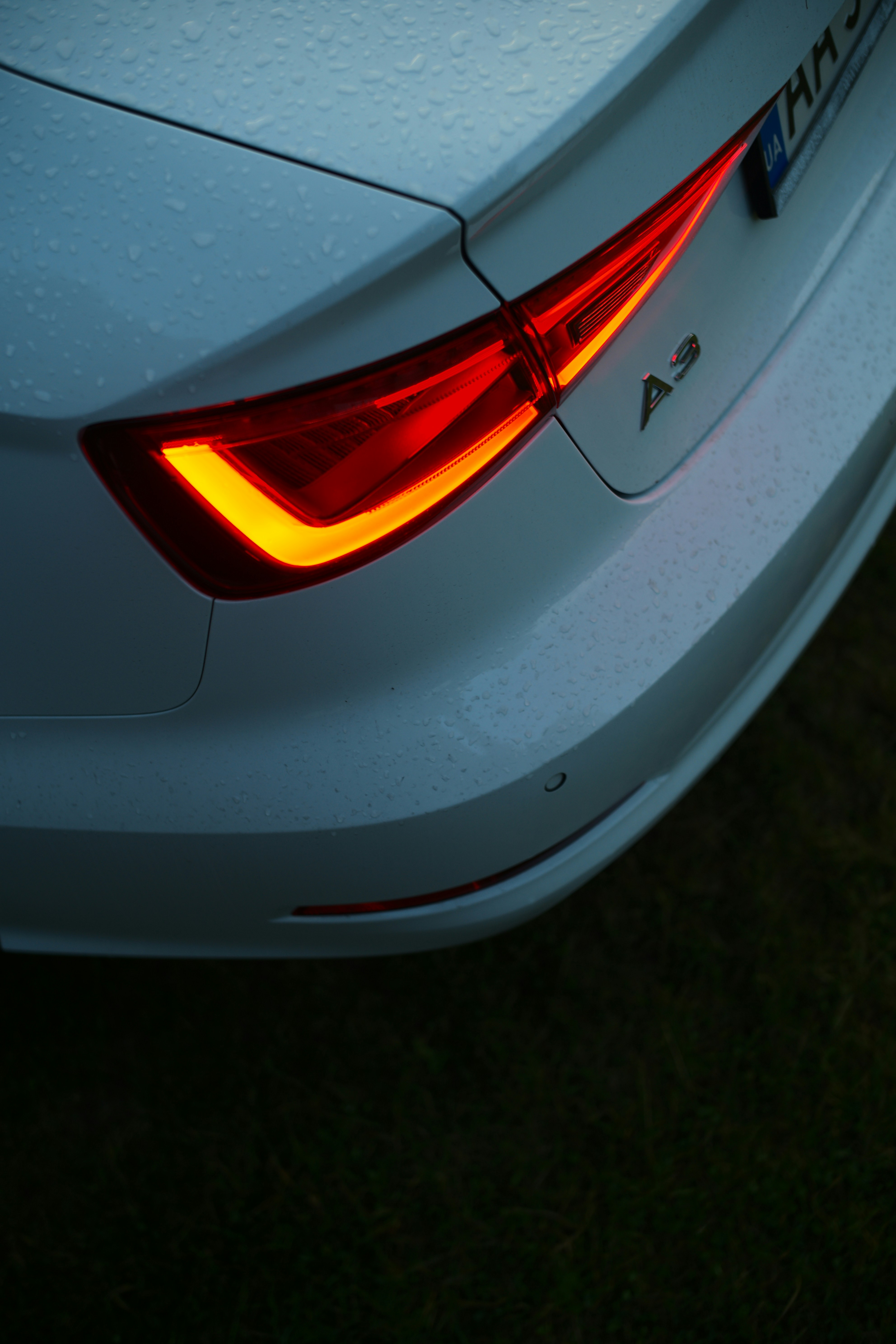 Rain-kissed Taillamp: Close-Up of a White Audi A3's Red Glow