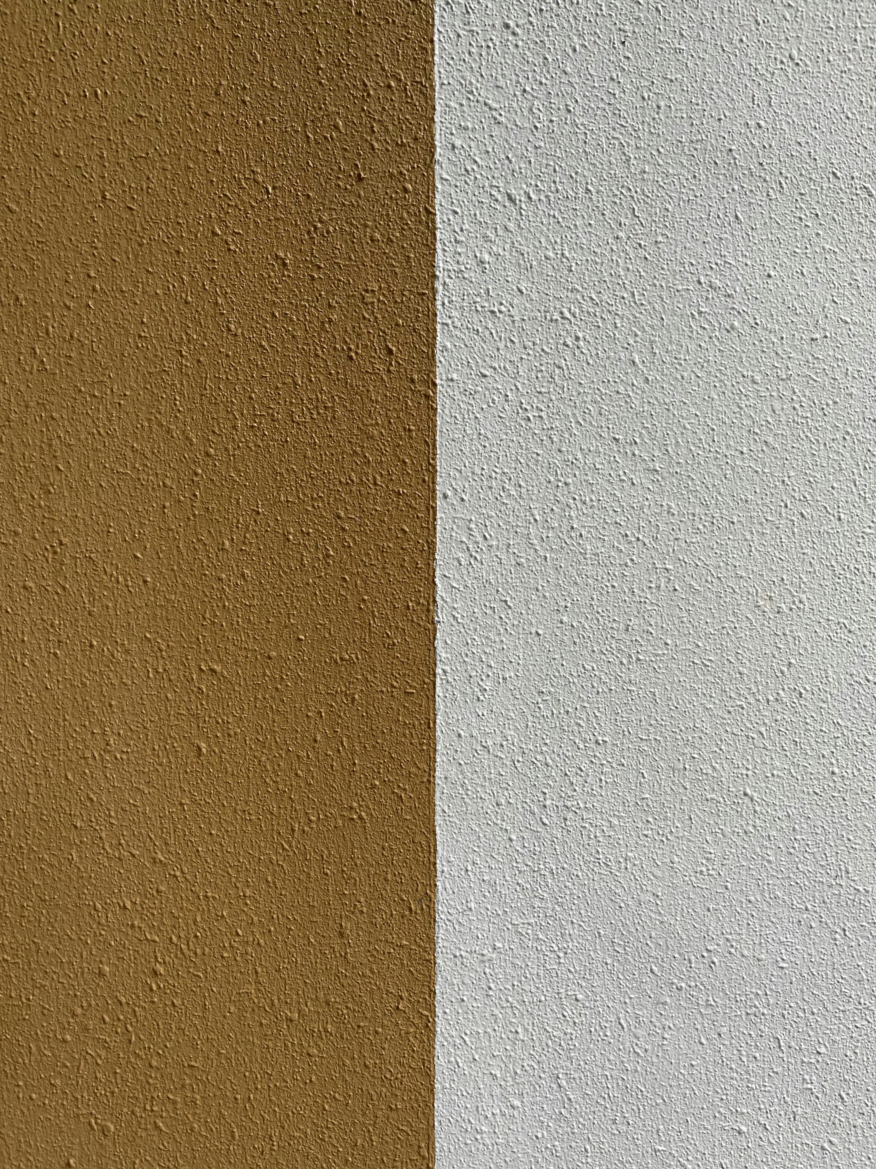 Divided wall featuring a textured brown section on the left and a smooth white section on the right.