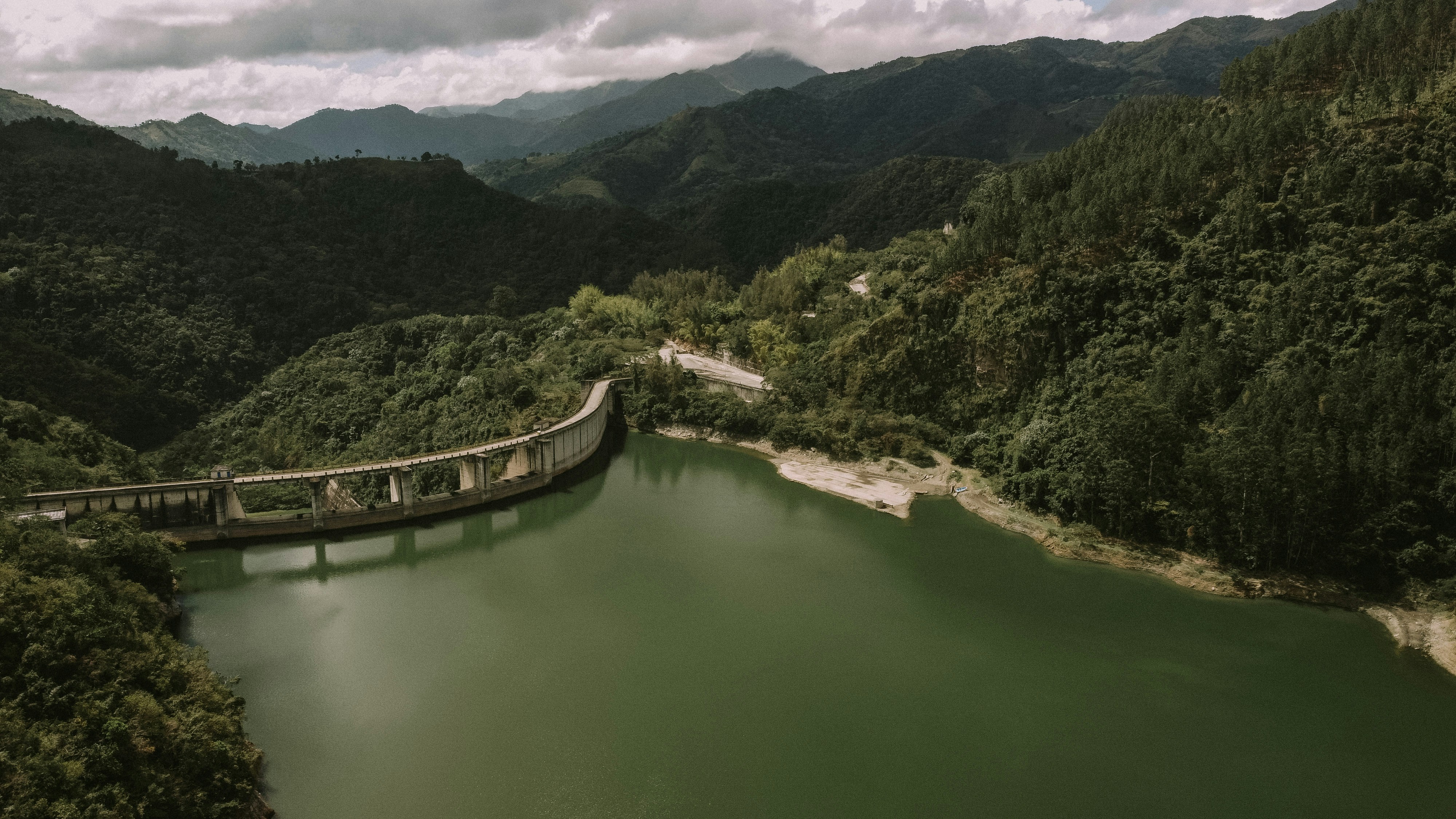 Brown wooden bridge over river between green mountains during daytime ...