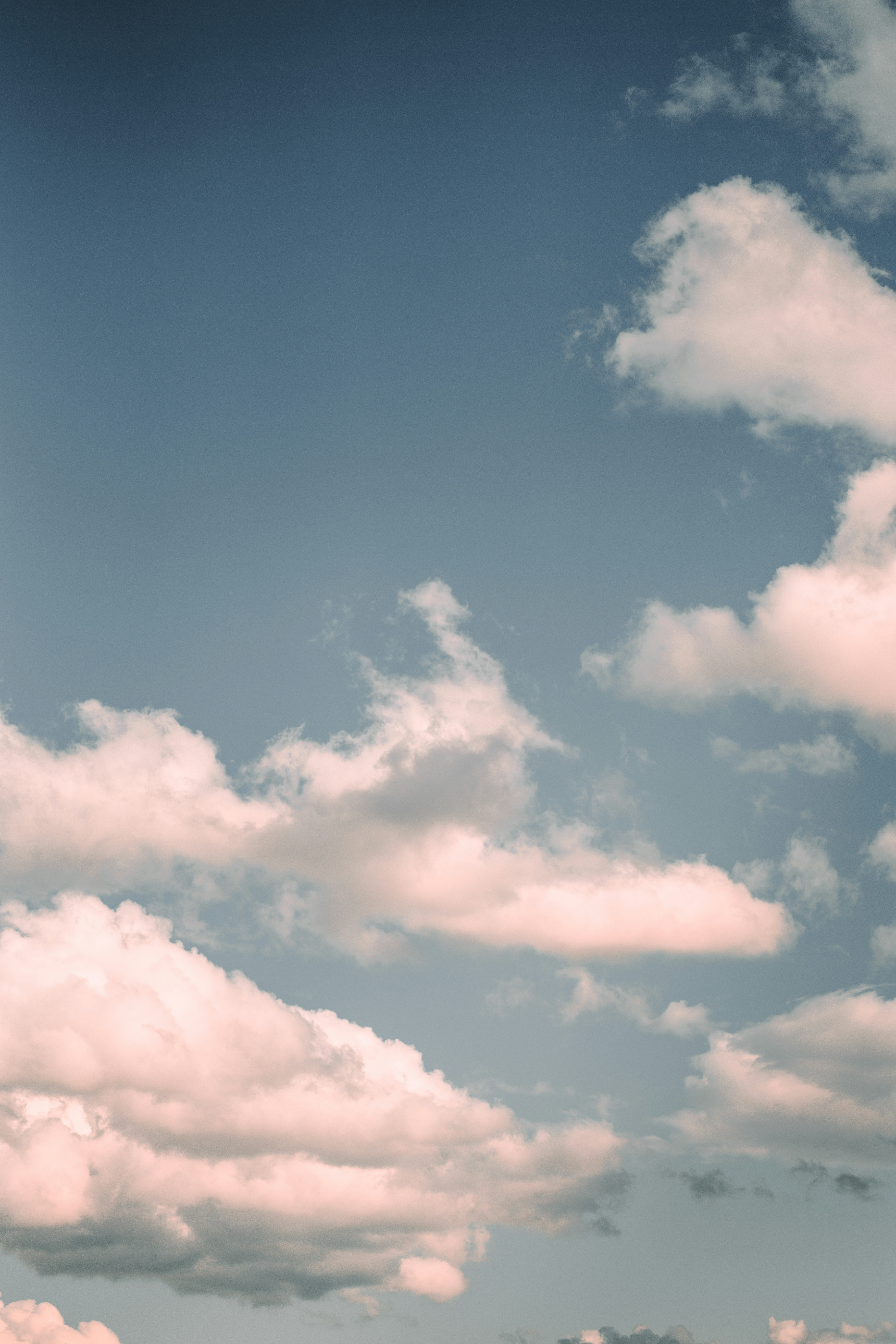Soft, fluffy clouds drifting across a serene blue sky, creating a tranquil atmosphere.