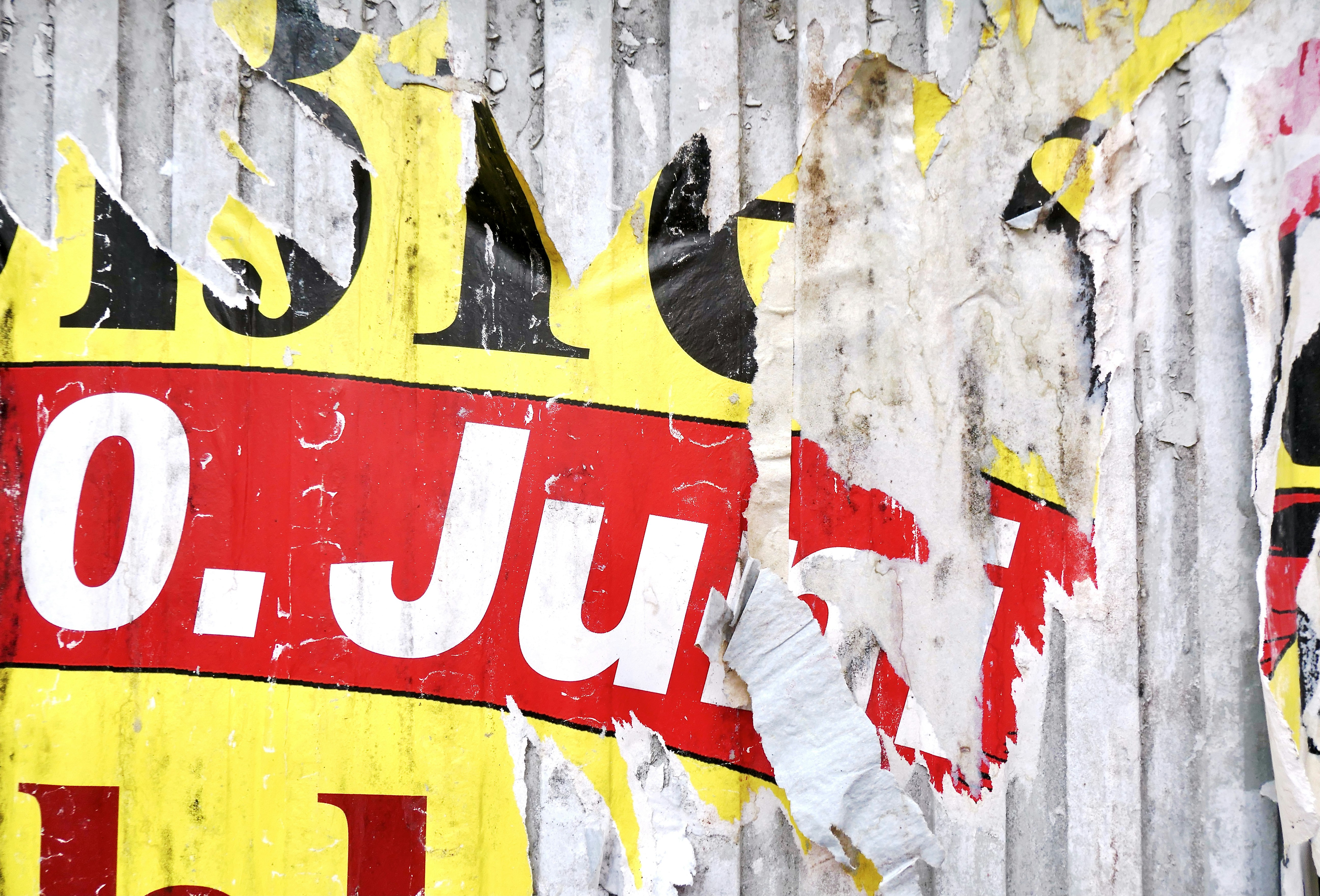 Torn Yellow-Red Poster Peel on Weathered Wall