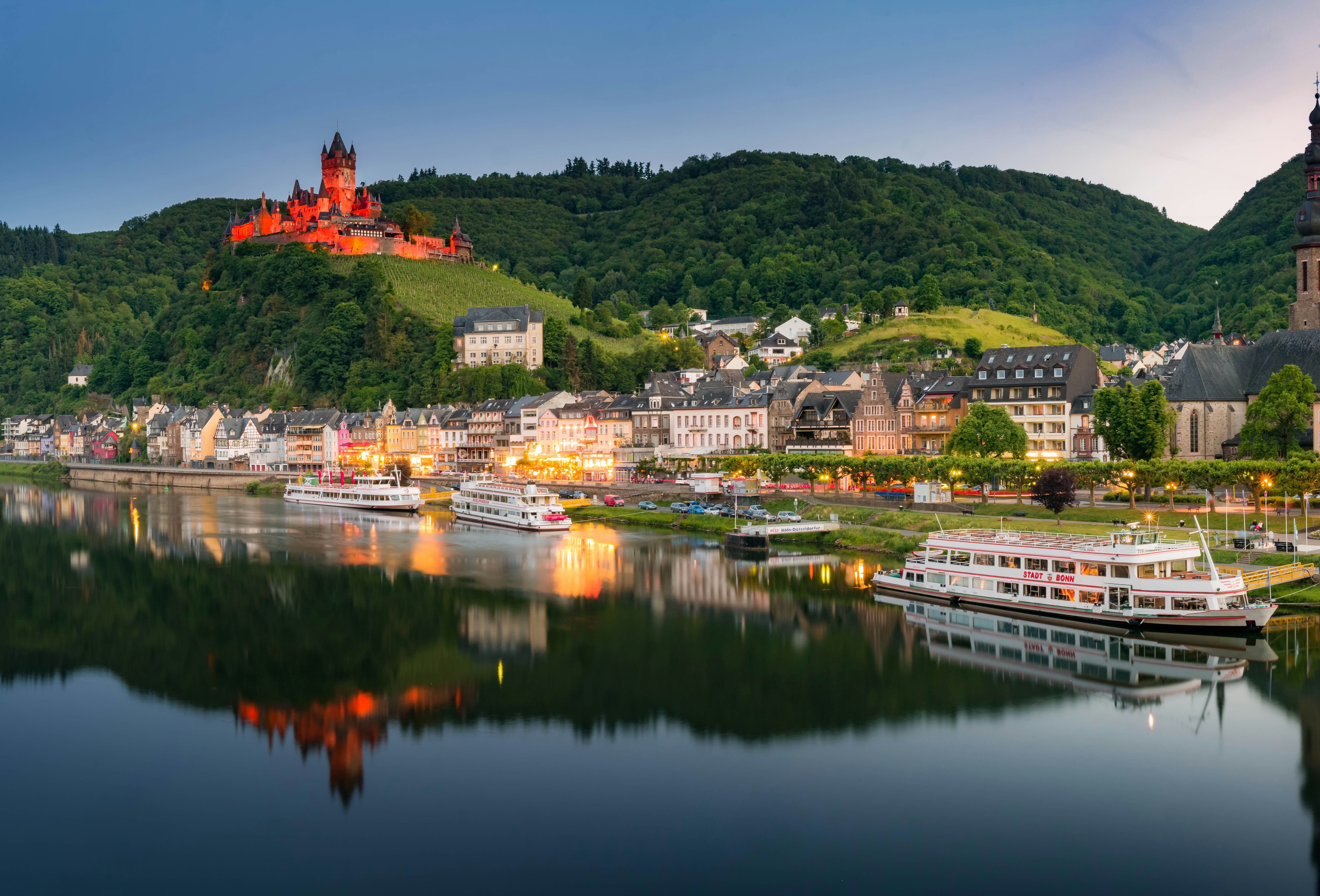 Crimson Fortress at Dusk Over a Tranquil Riverfront Town