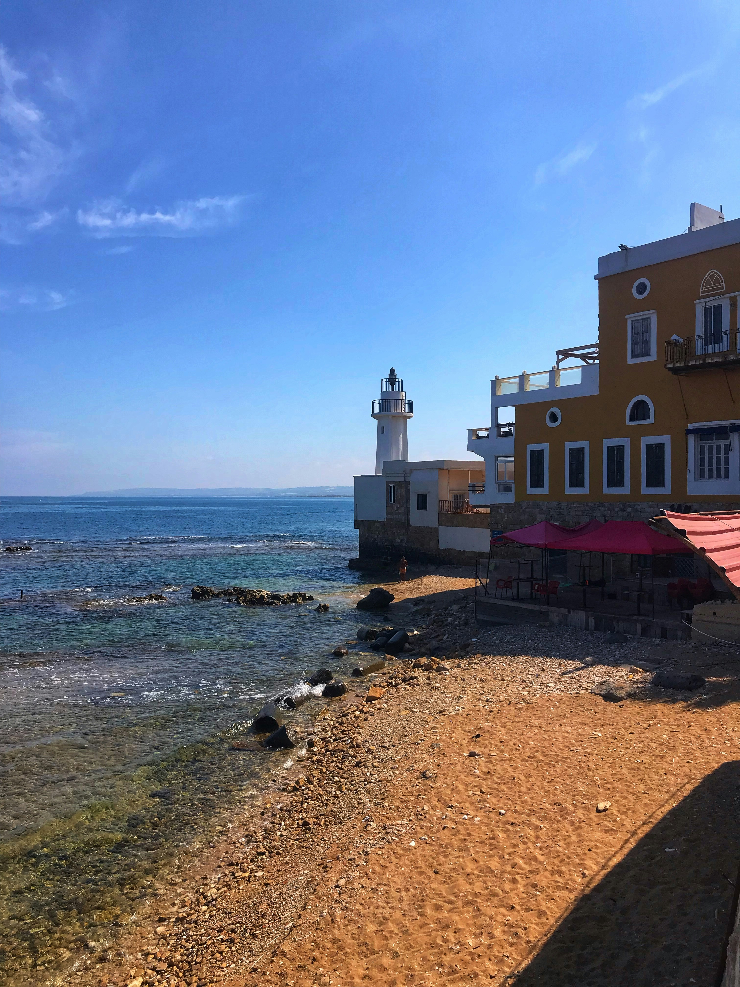 Red and white concrete building near sea during daytime photo – Free ...
