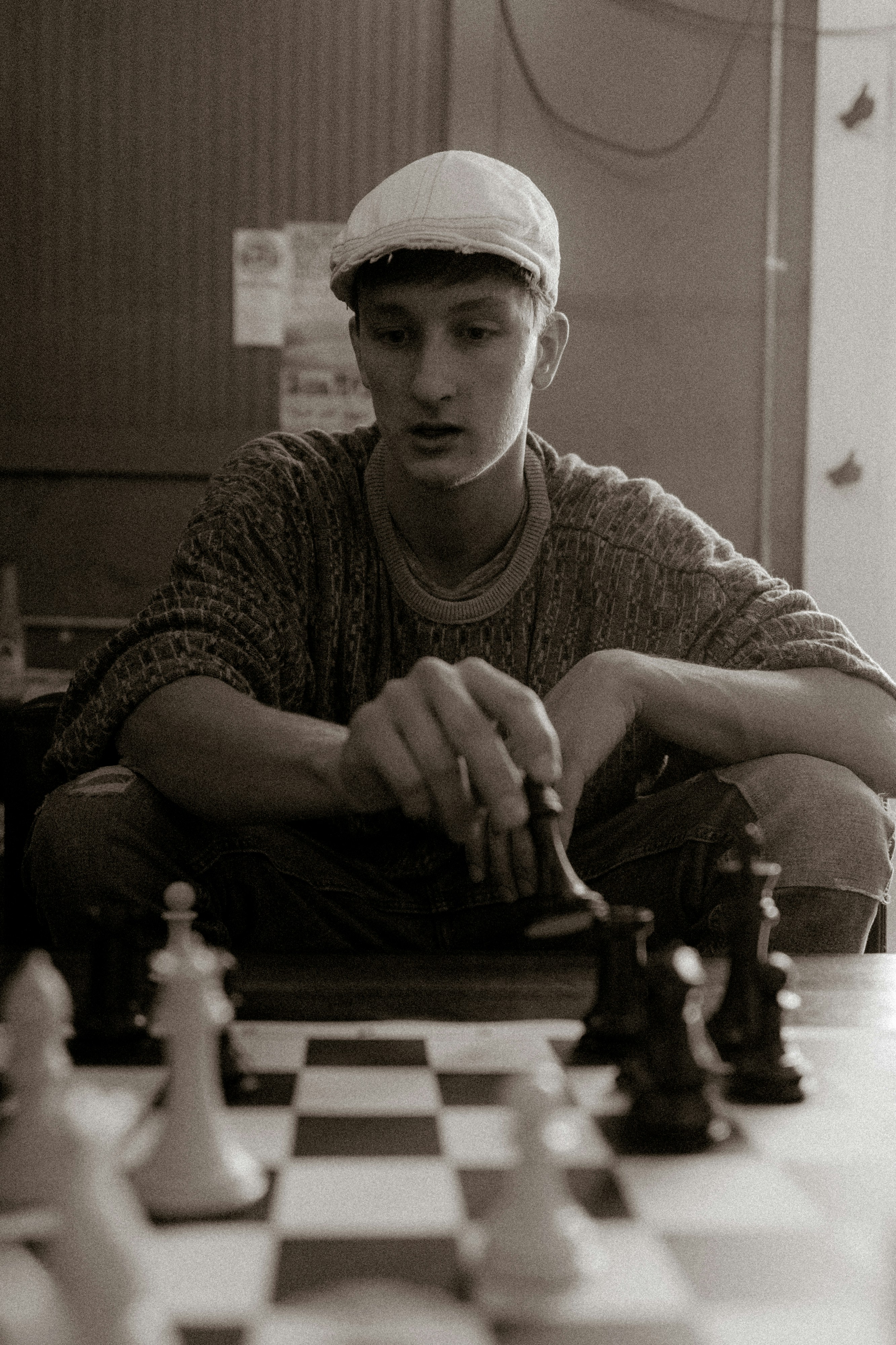 Young man deep in thought while playing chess, surrounded by an atmosphere of concentration and strategy.