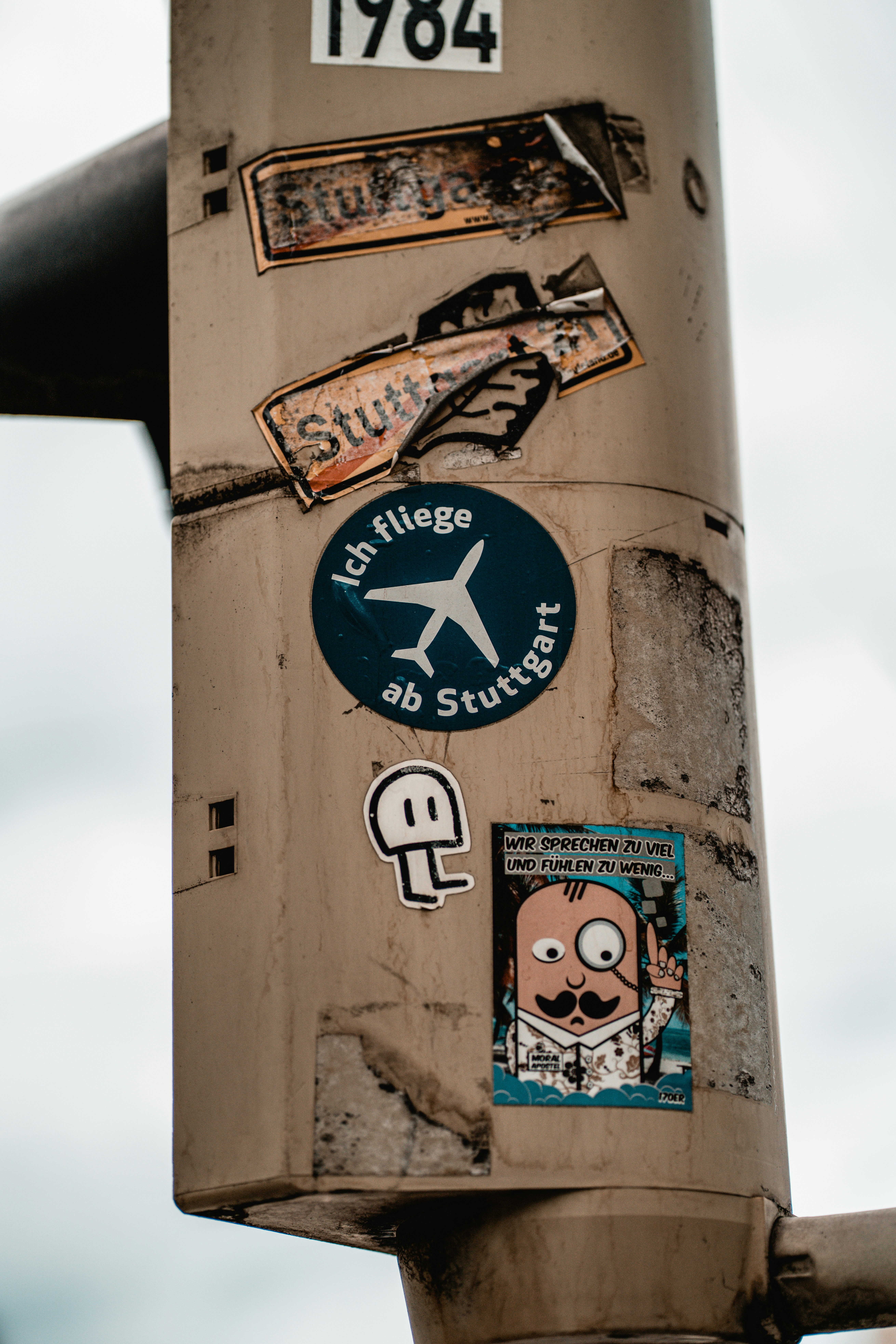 Stickered Pillar of Stuttgart: Weathered Pole Adorned with Wanderer Emblems