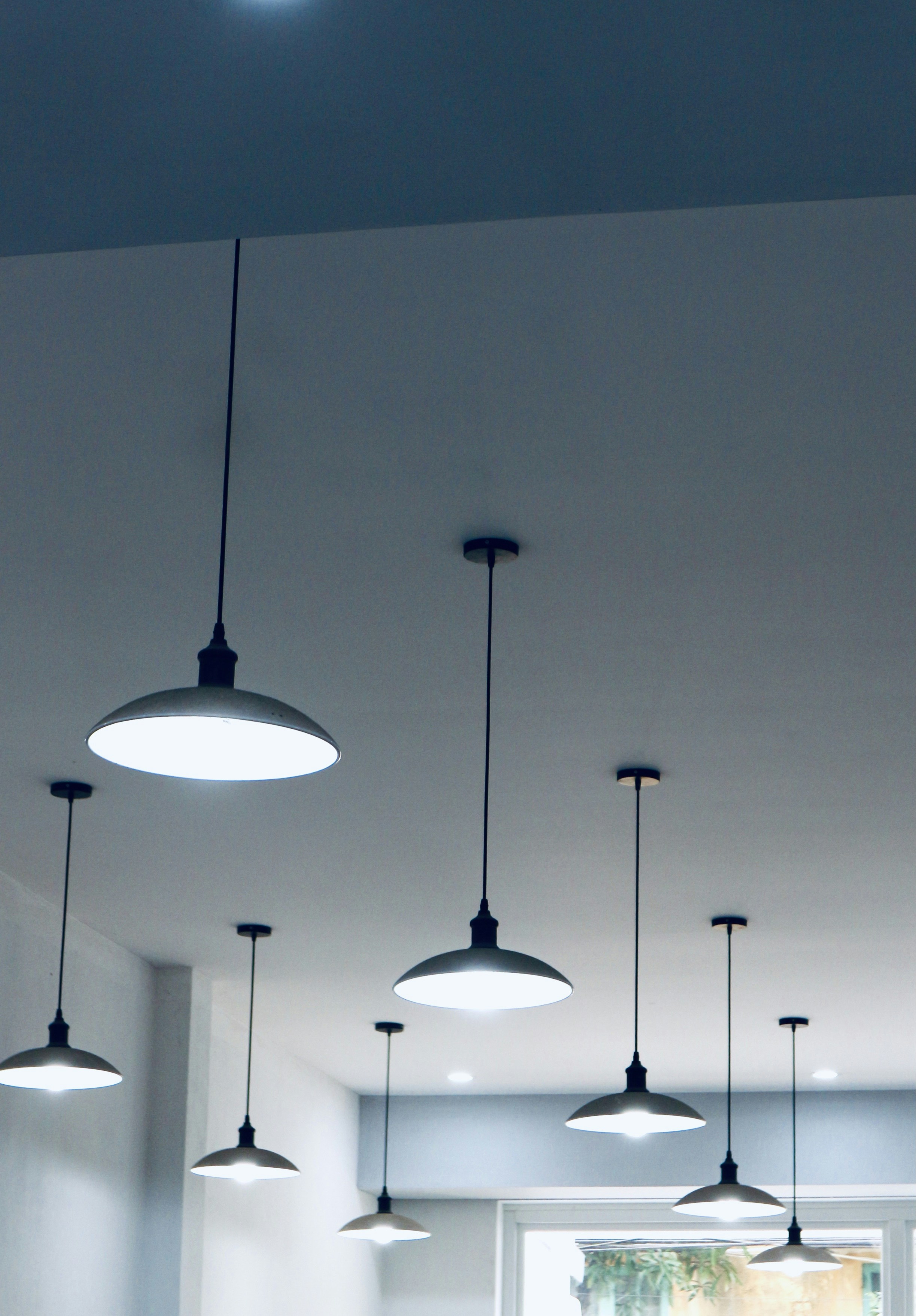 A series of industrial-style pendant lights hanging from a ceiling, casting a soft glow in a modern interior space.