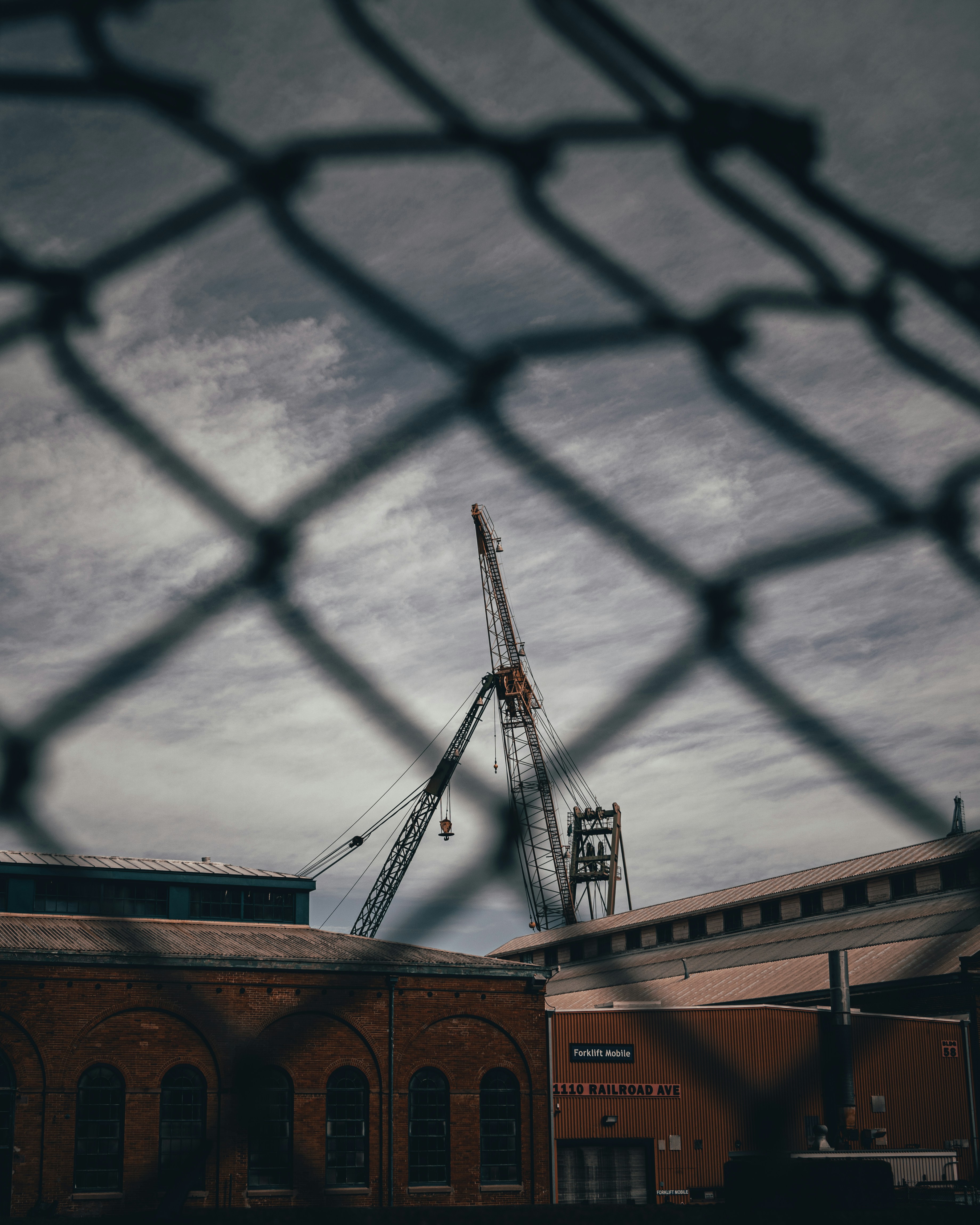 Industrial Crane Rising Above a Chain-Link Frame