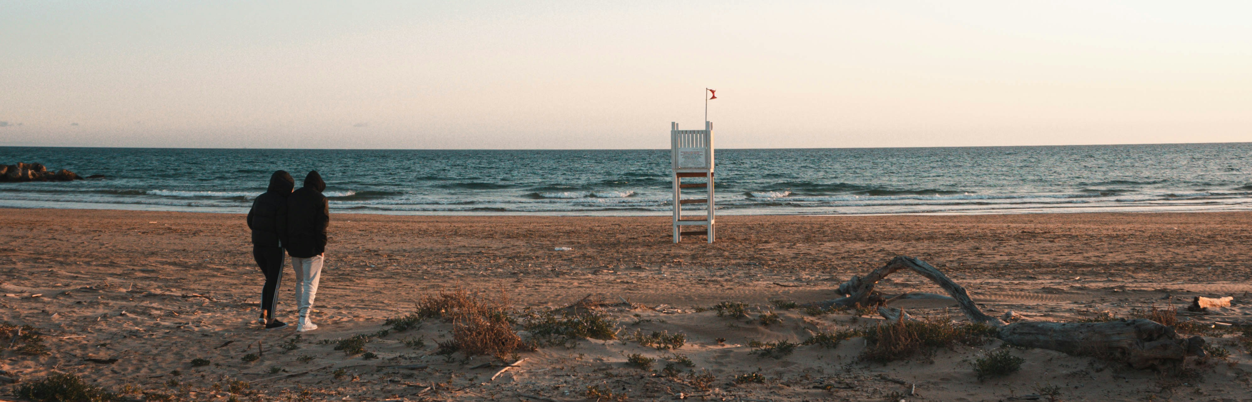 Twilight Crossing: Silhouettes and a Lifeguard Chair on a Quiet Beach