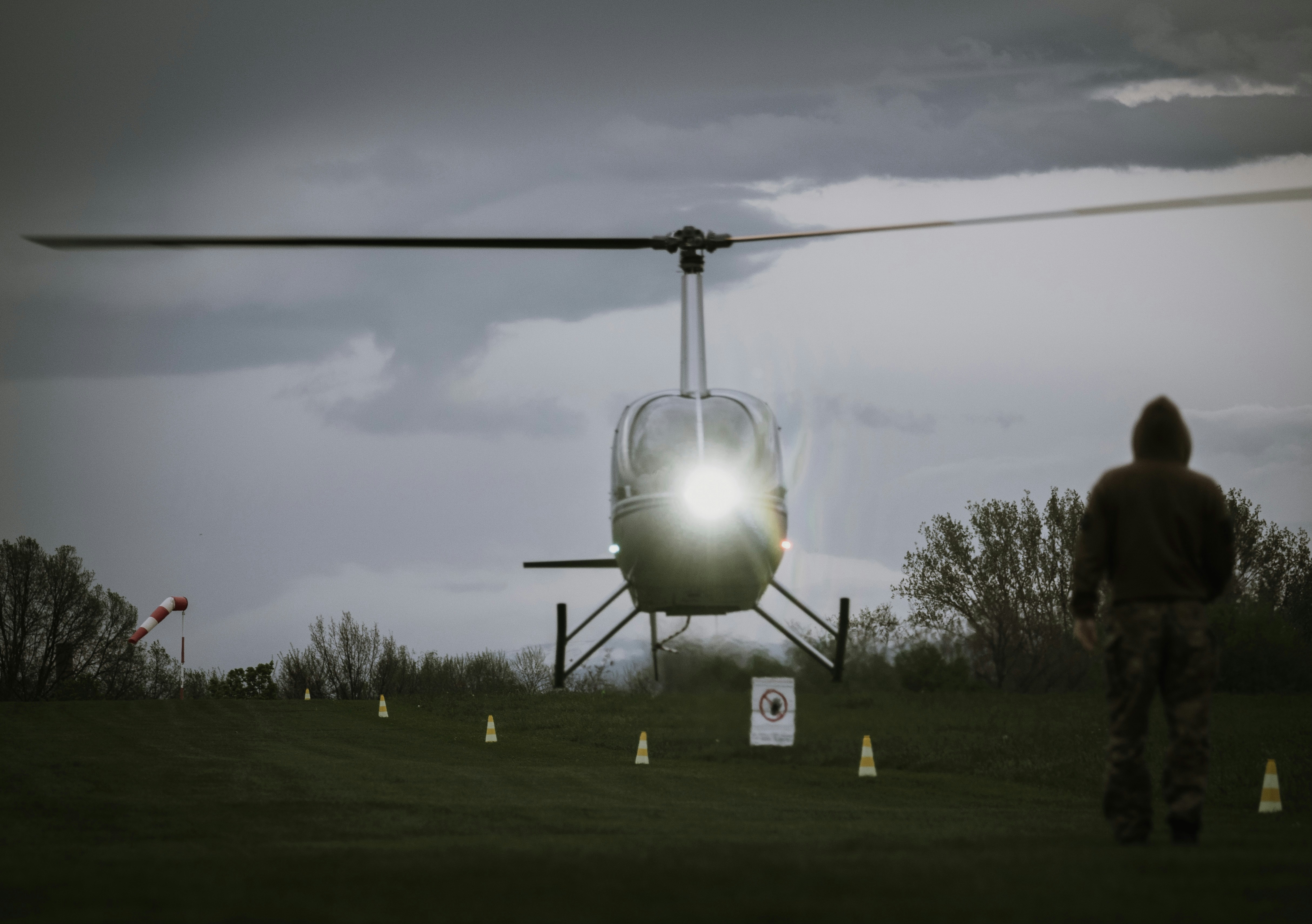 Helicopter Approach: A Ground Crew Stands Vigil as the Spotlight Bites the Haze