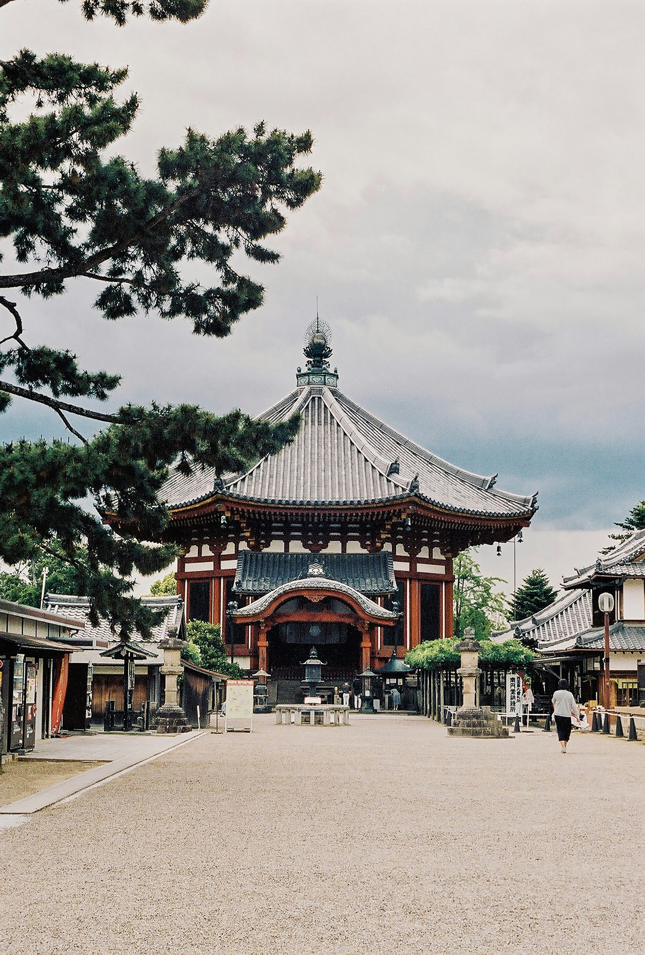Traditional Japanese pagoda with intricate roof details surrounded by lush trees and a cloudy sky.