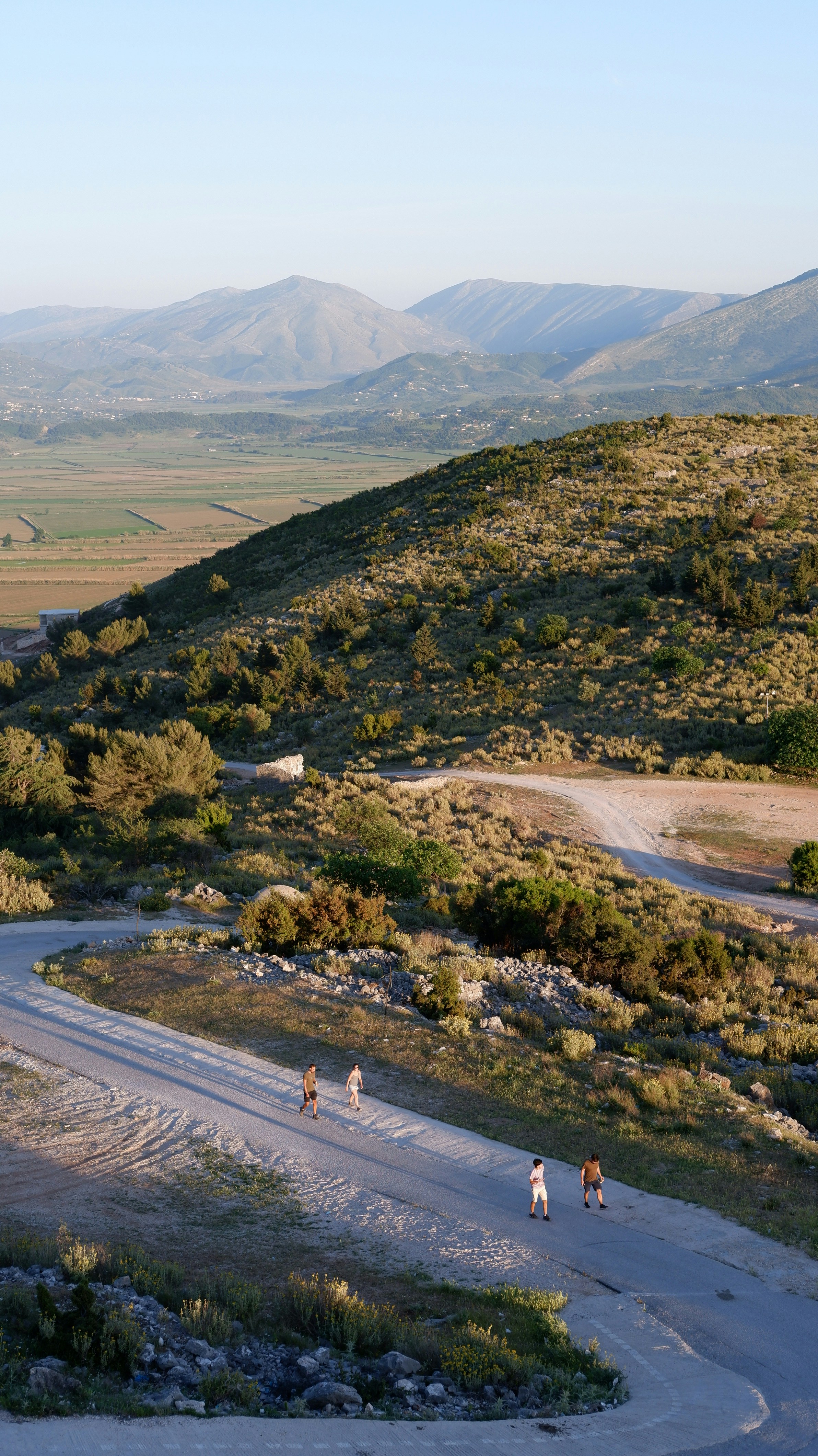 Sunlit Ridge Walk: Hikers on a Quiet Curving Trail Beneath Distant Peaks