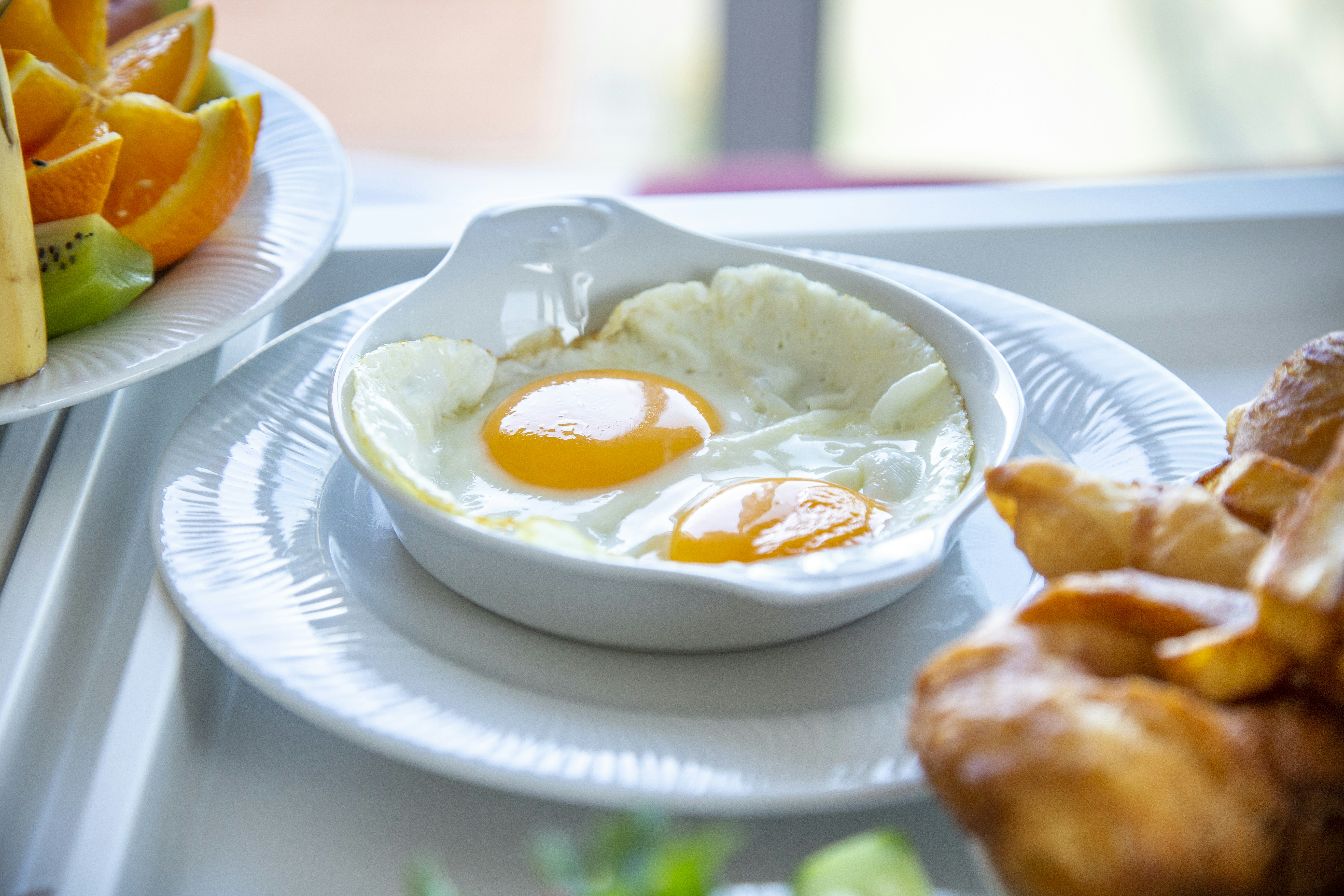 Sunny Breakfast Trio: Fried Eggs in White Dish with Croissant and Fruit Ring