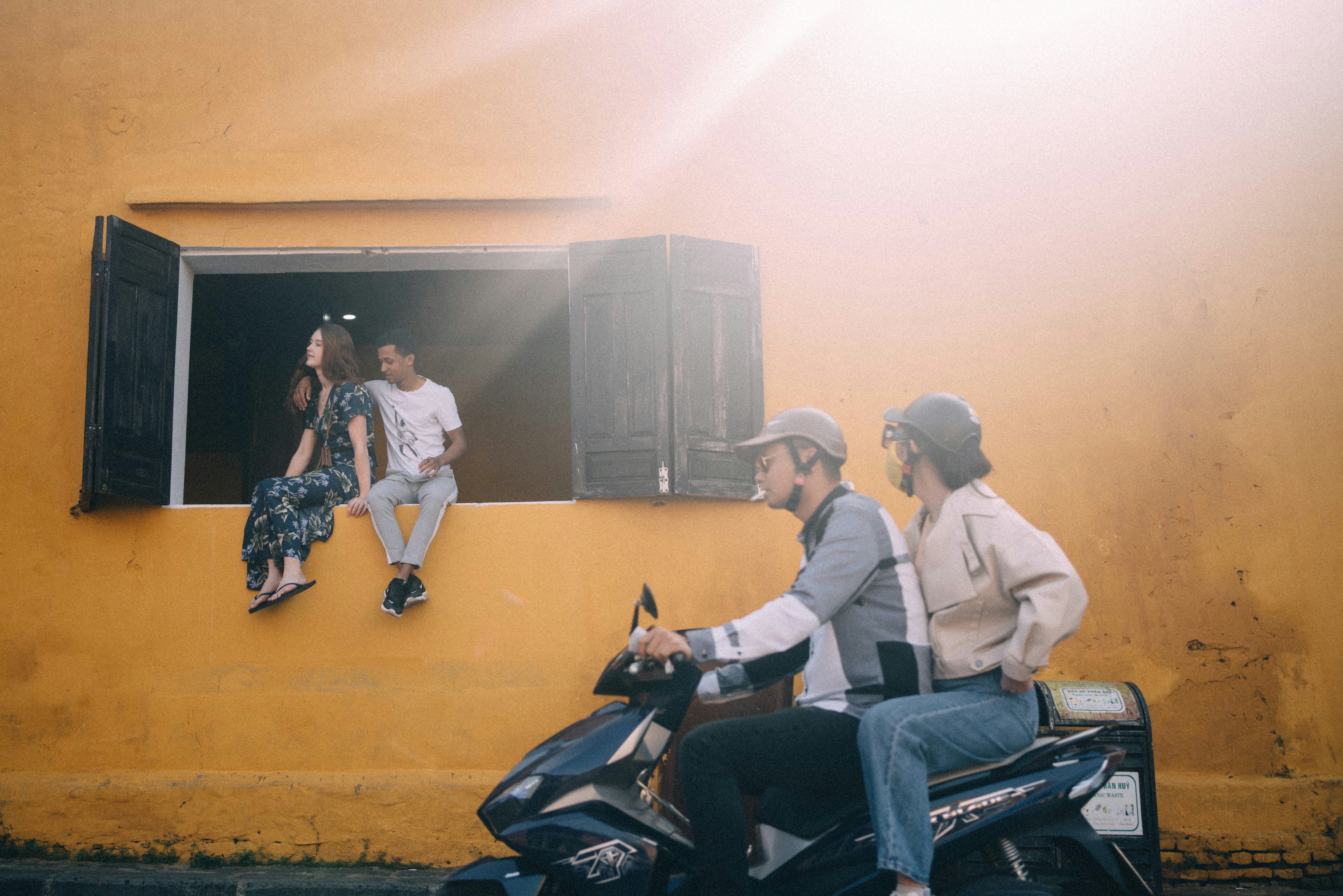 Riders in Motion Past a Warm Yellow Wall