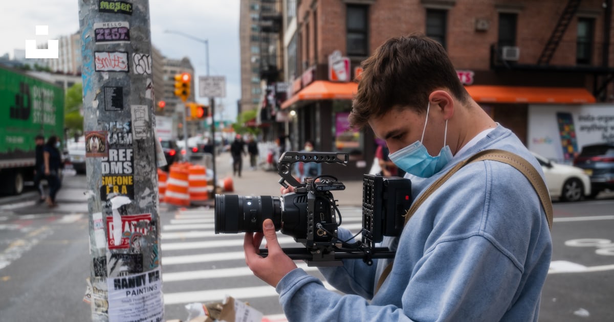 Foto Hombre Con Chaqueta Azul Sosteniendo Una Cámara Dslr Negra