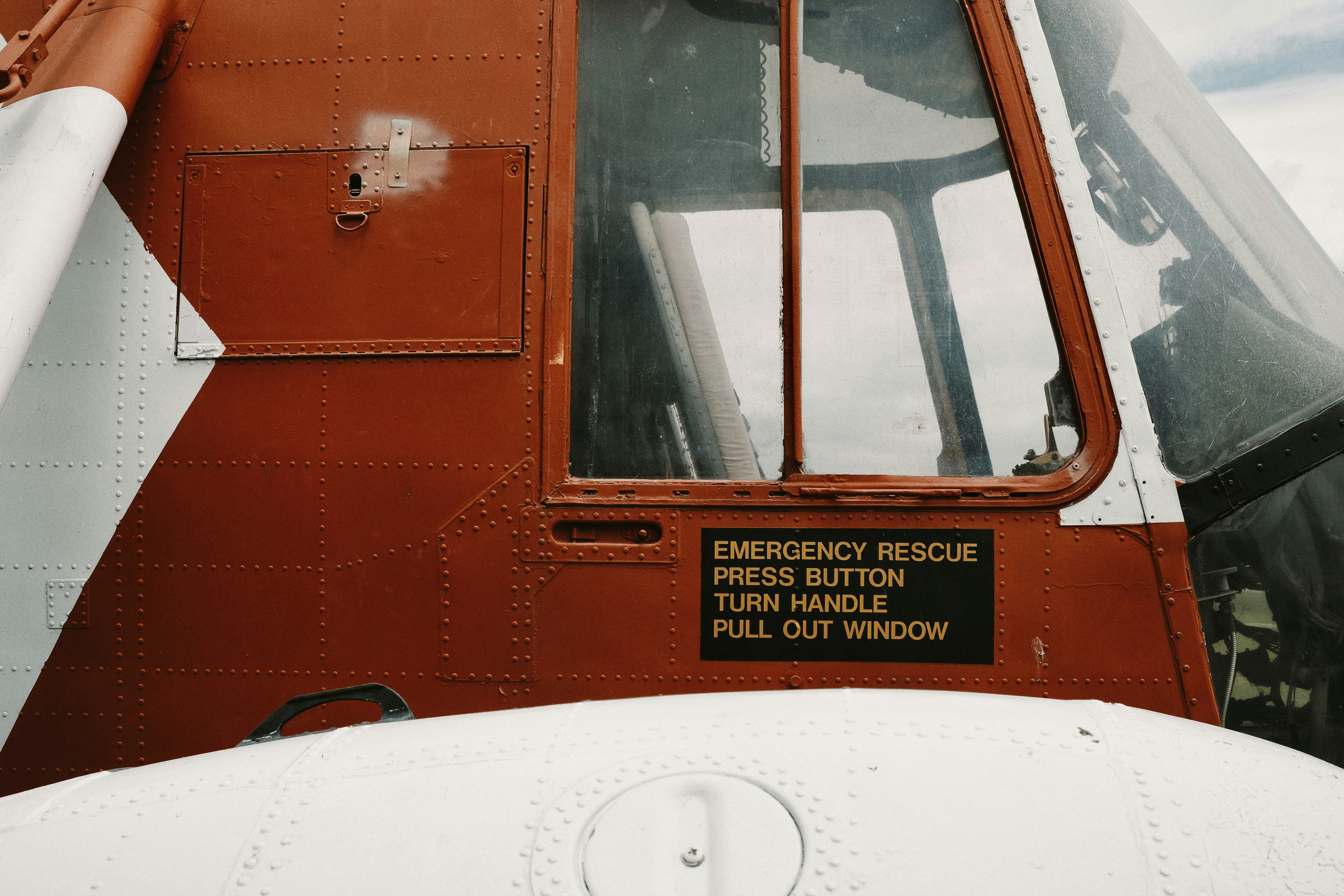 Close-up of an emergency window mechanism on a helicopter, highlighting crucial safety instructions for passengers.