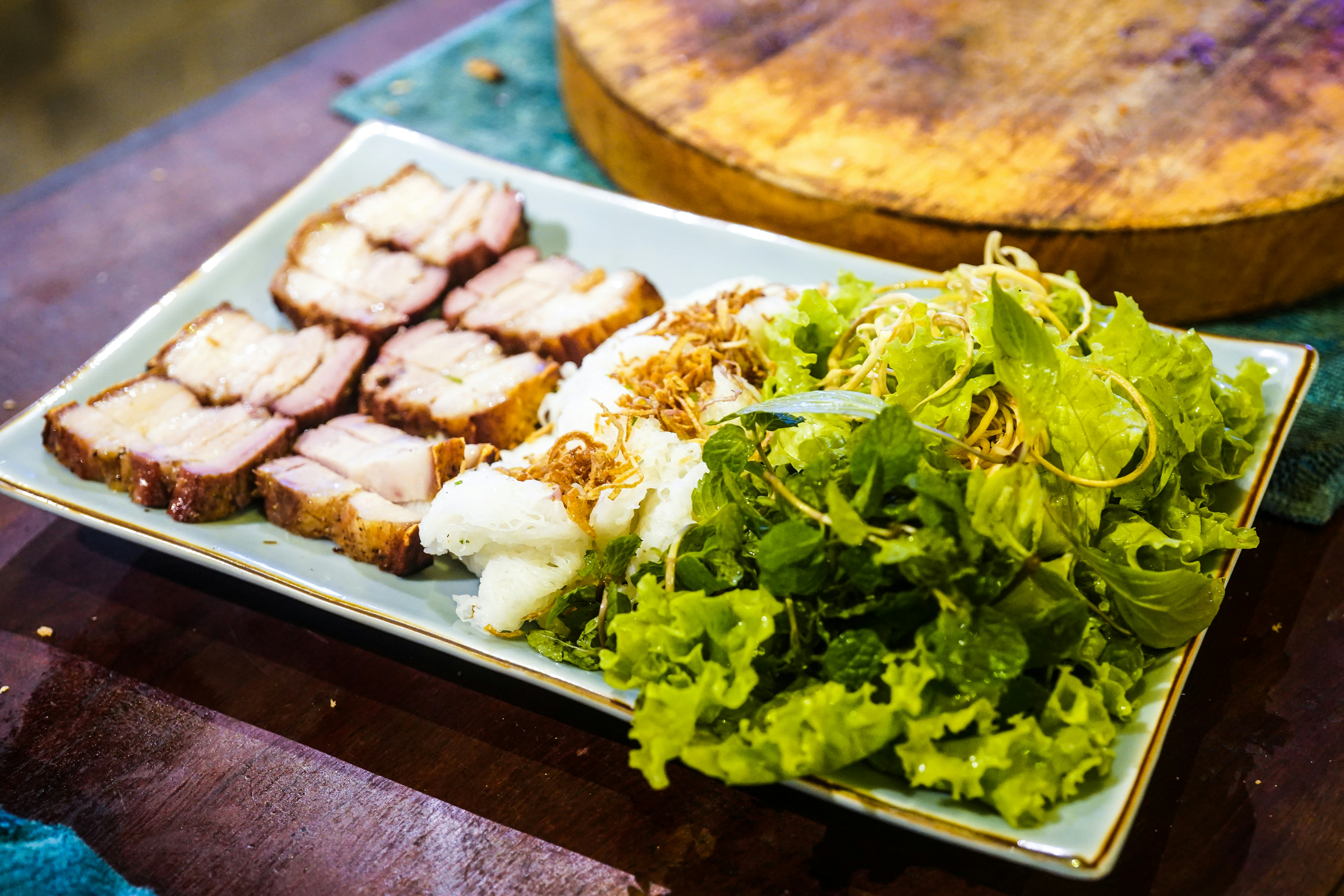 A beautifully arranged plate featuring succulent slices of roasted pork alongside a vibrant salad of fresh greens and herbs, showcasing a delightful culinary experience.
