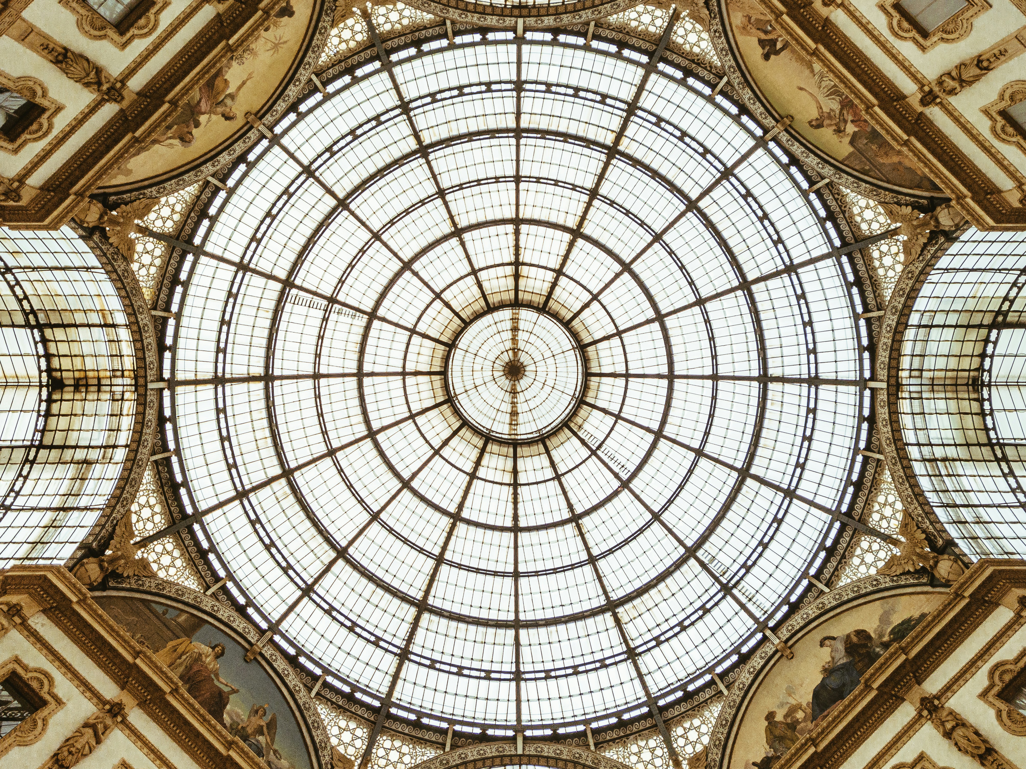 Ornate glass dome with intricate metal framework and classical artwork details.