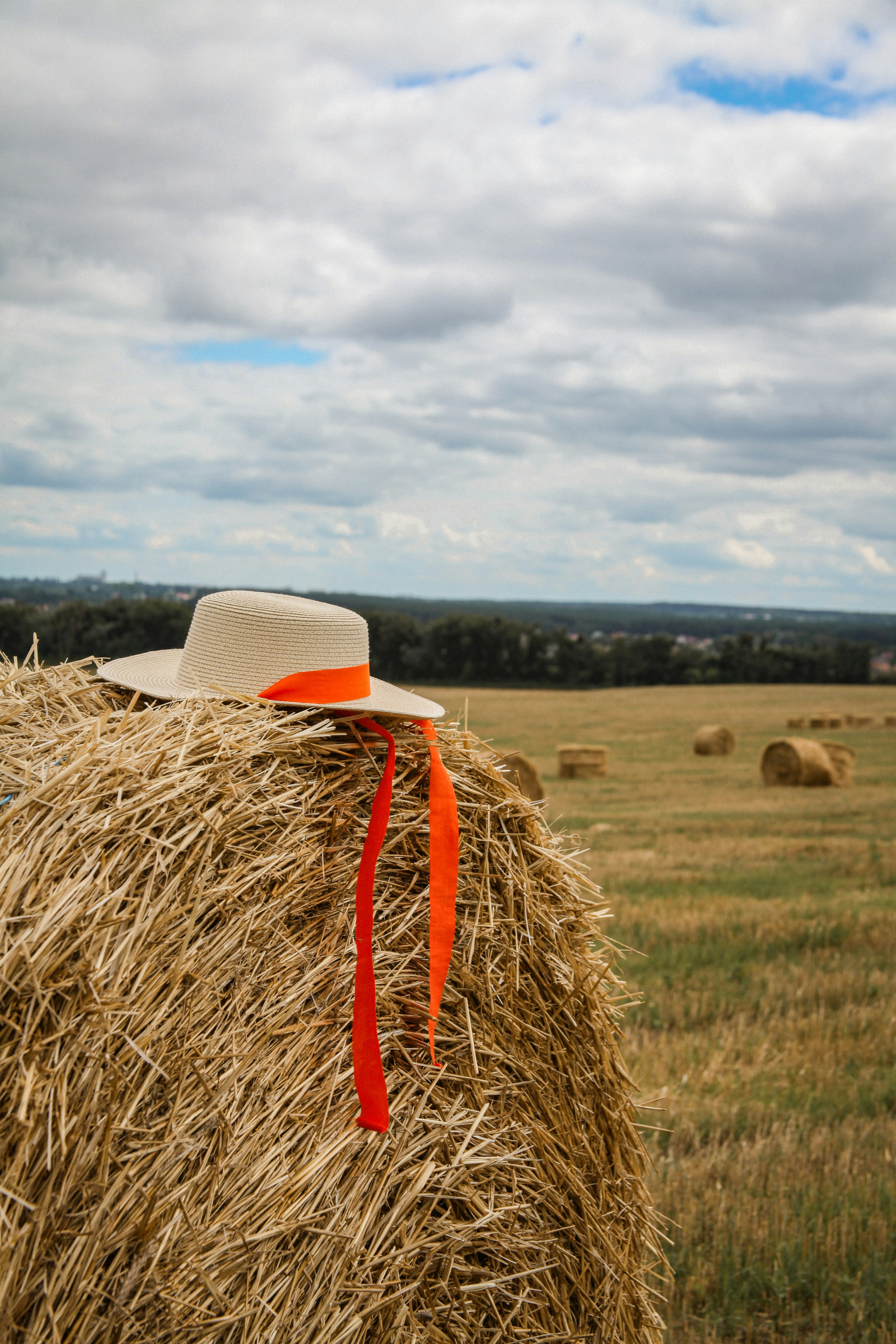 person in white knit cap standing on brown grass field under white clouds during daytime