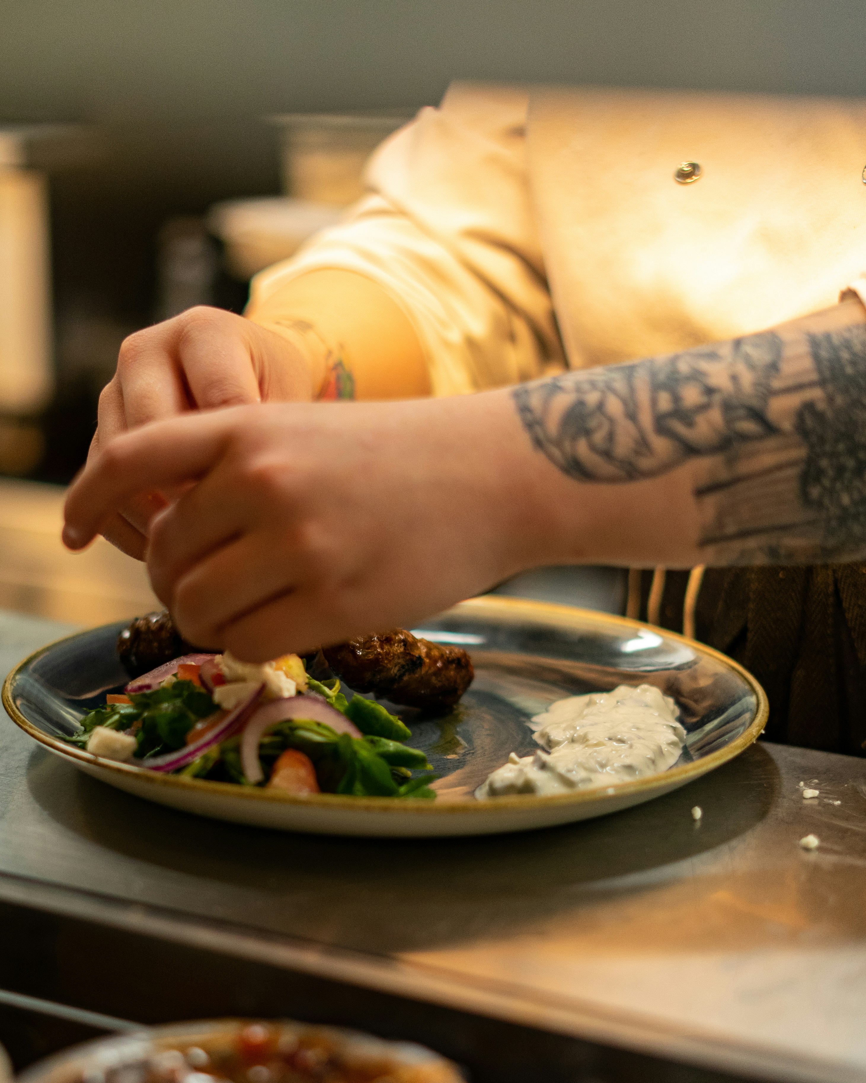 Plating Precision: Tattooed Hands Finish a Blue-Rimmed Dish