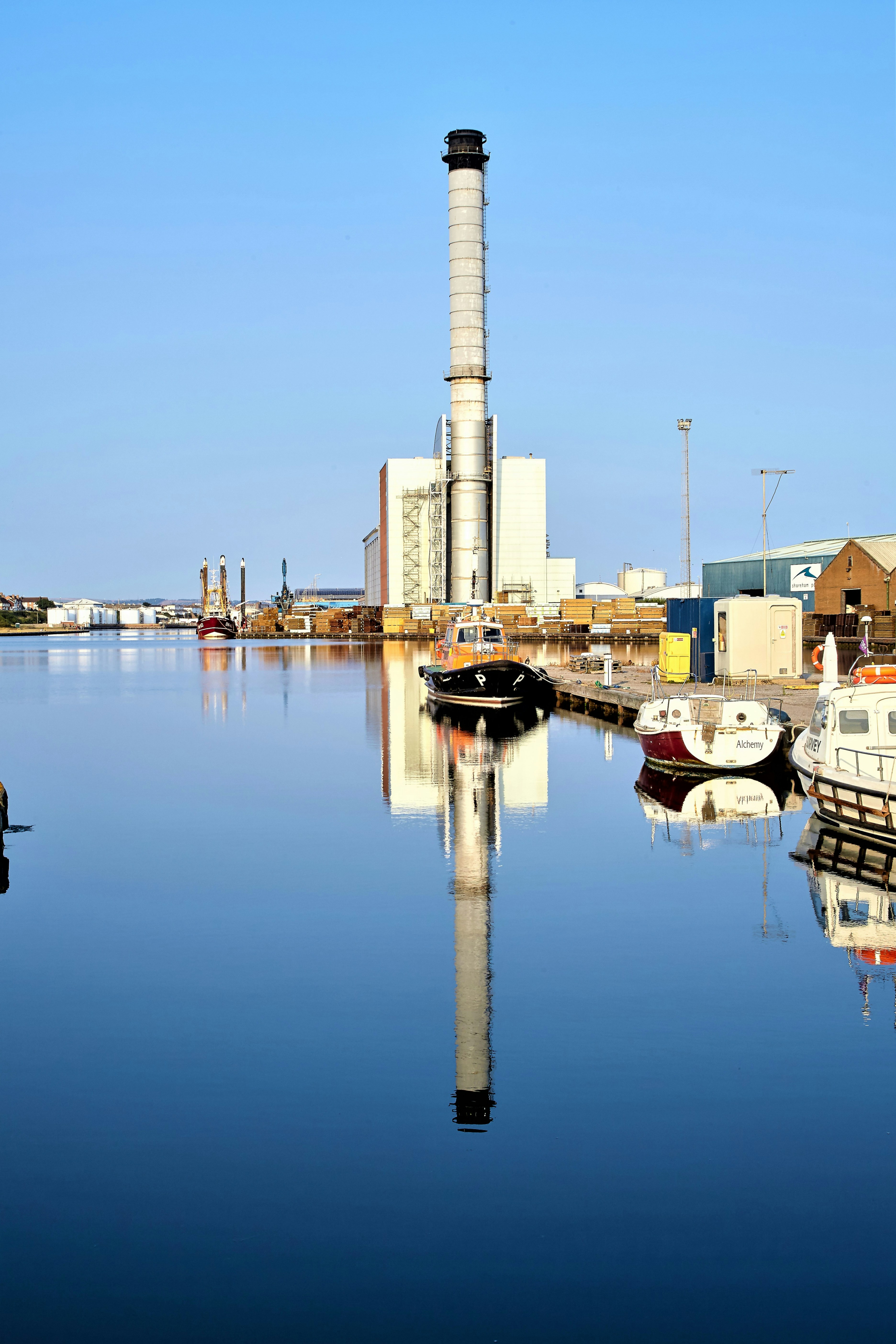 Concrete Chimney Over a Glassy Harbor: A Mirror-Quiet Industrial Portrait