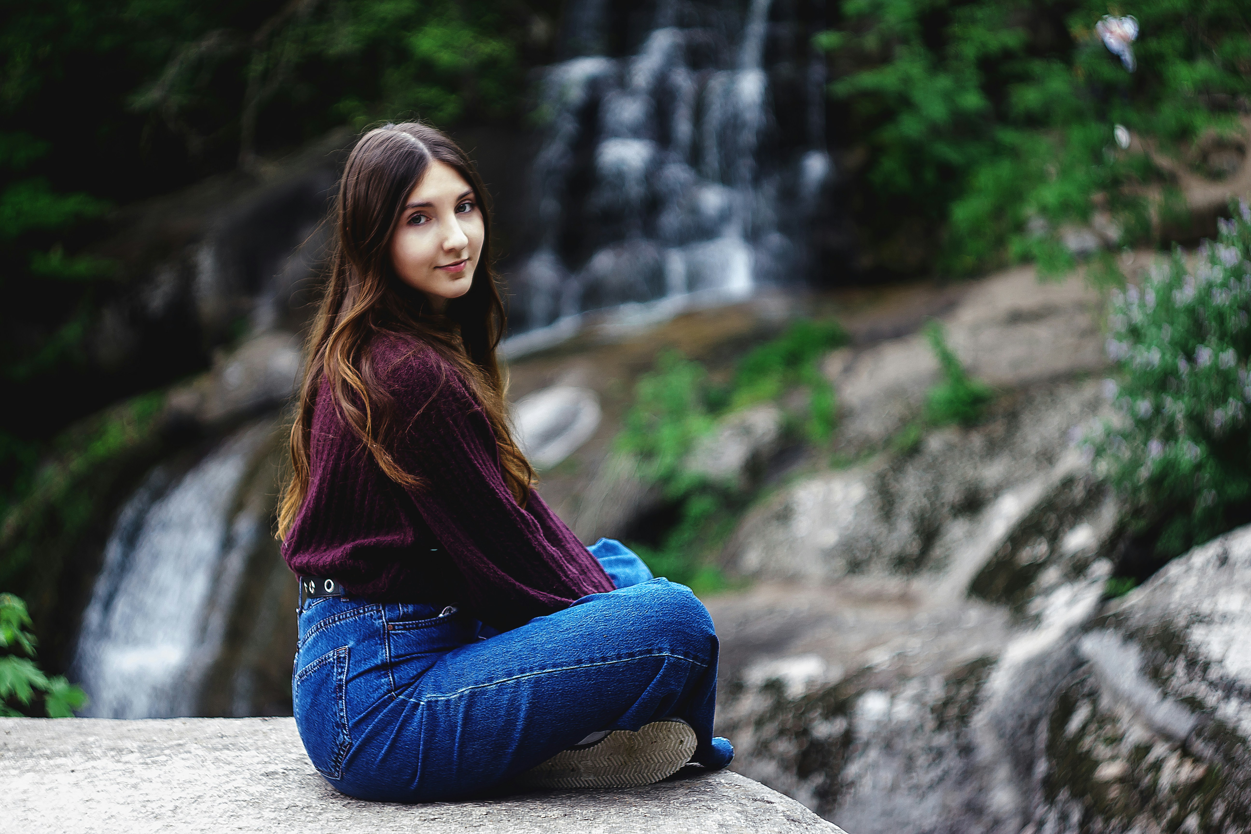 Portrait by the Falls: a burgundy-clad figure beside a mossy cascade
