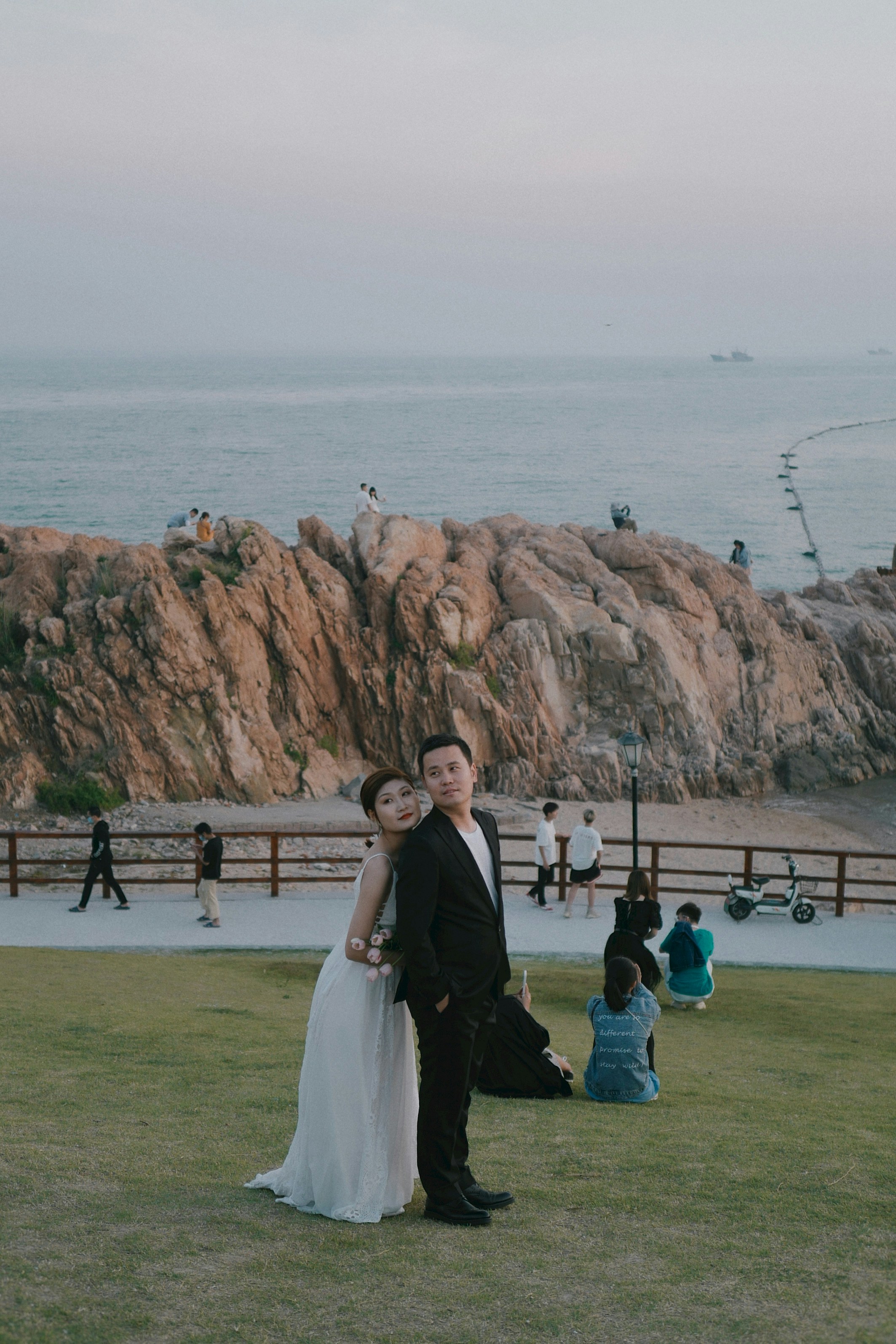 Woman in black dress standing on green grass field near brown rock ...