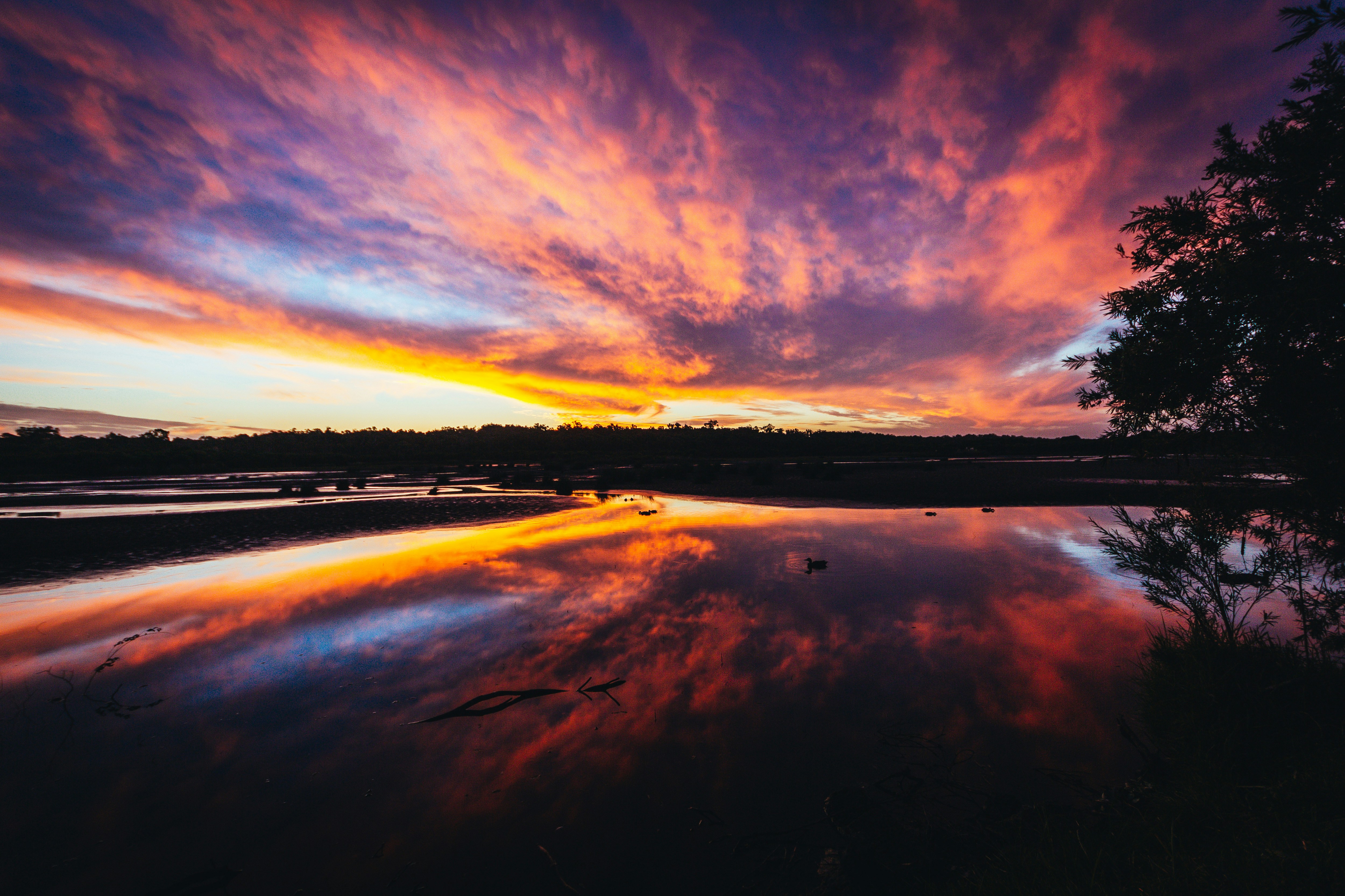 Horizon on Fire: Reflections of a Fiery Sunset Across a Glassy Lake