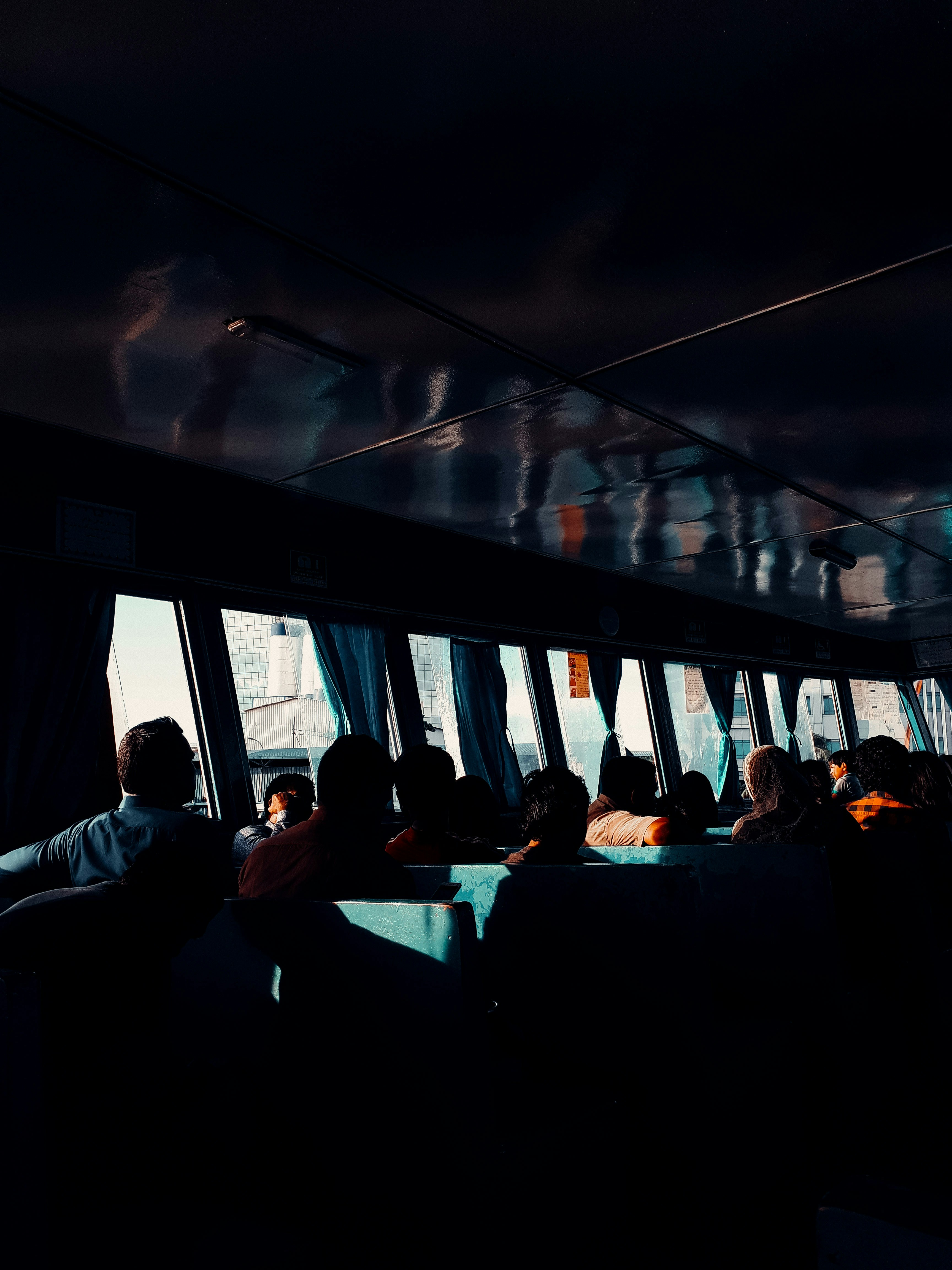 Passengers seated inside a ferry, illuminated by natural light streaming through the windows, creating a play of shadows and reflections.