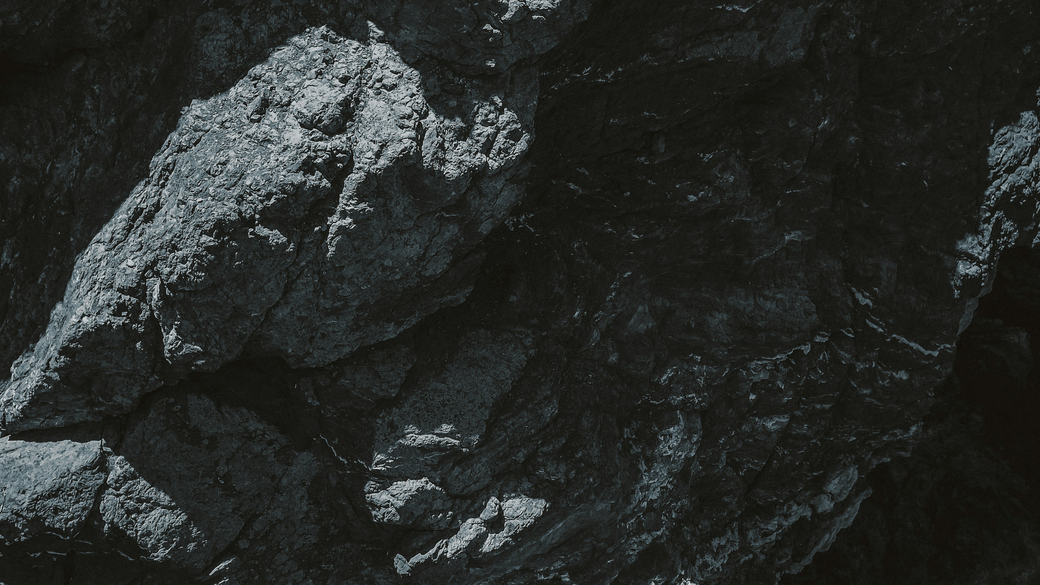 Intricate patterns of rugged rock surface showcasing a play of light and shadow. The image highlights the natural textures and geological features.