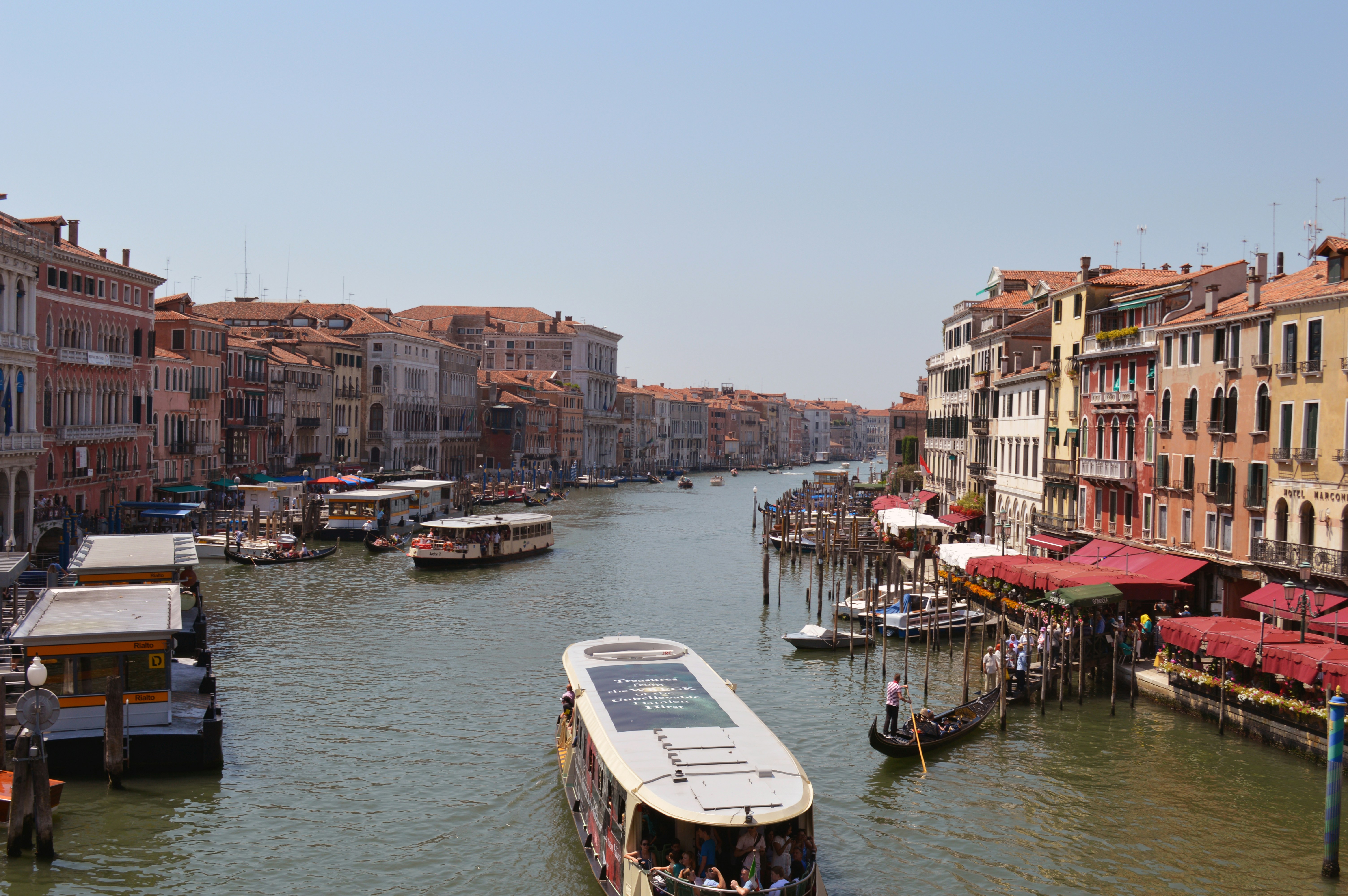 Vibrant scene of boats navigating the Grand Canal, flanked by historic buildings and bustling waterfront cafés.