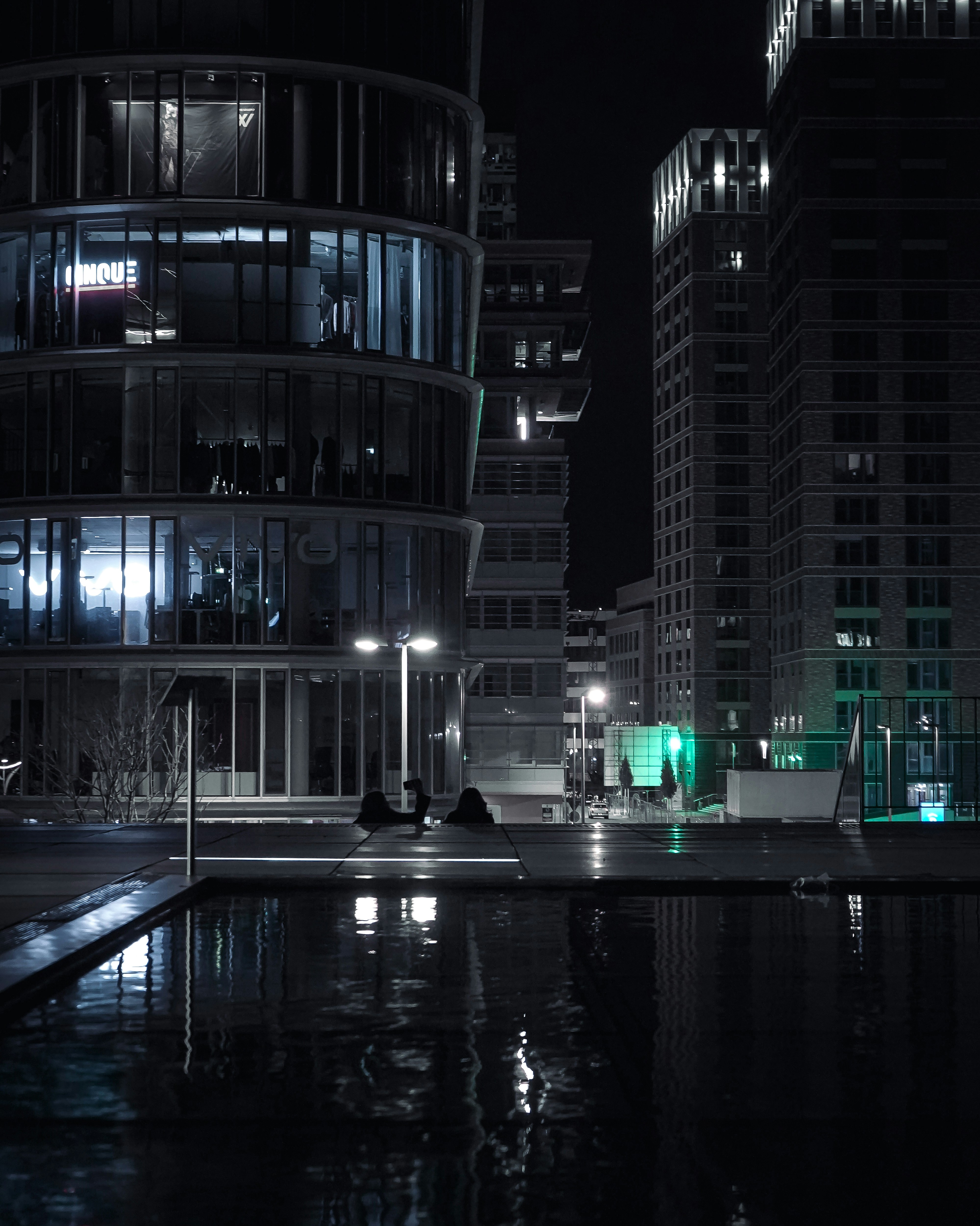 People walking on sidewalk near high rise buildings during night time ...