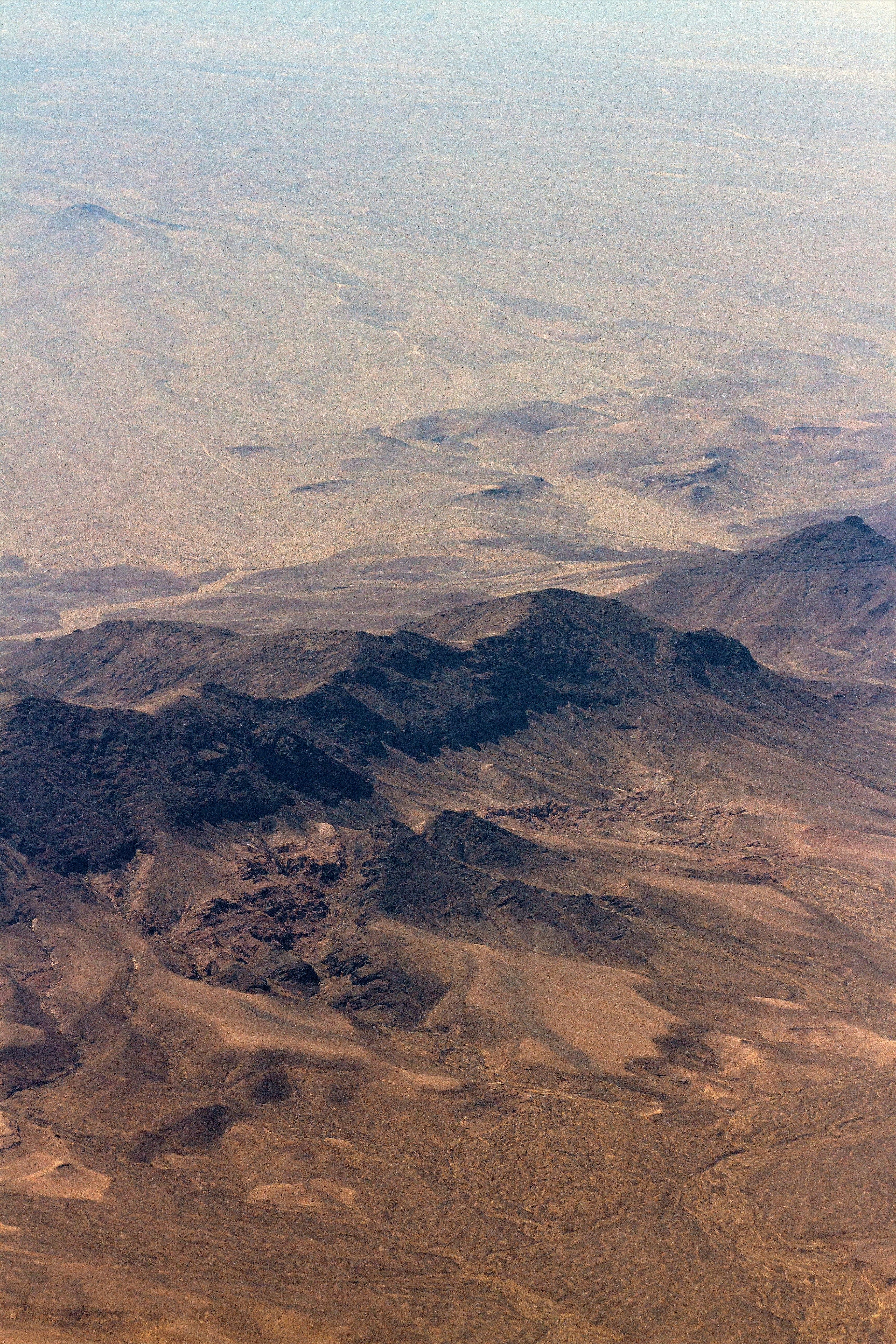 Aerial view of rugged desert landscape showcasing intricate patterns of rock formations and arid terrain.