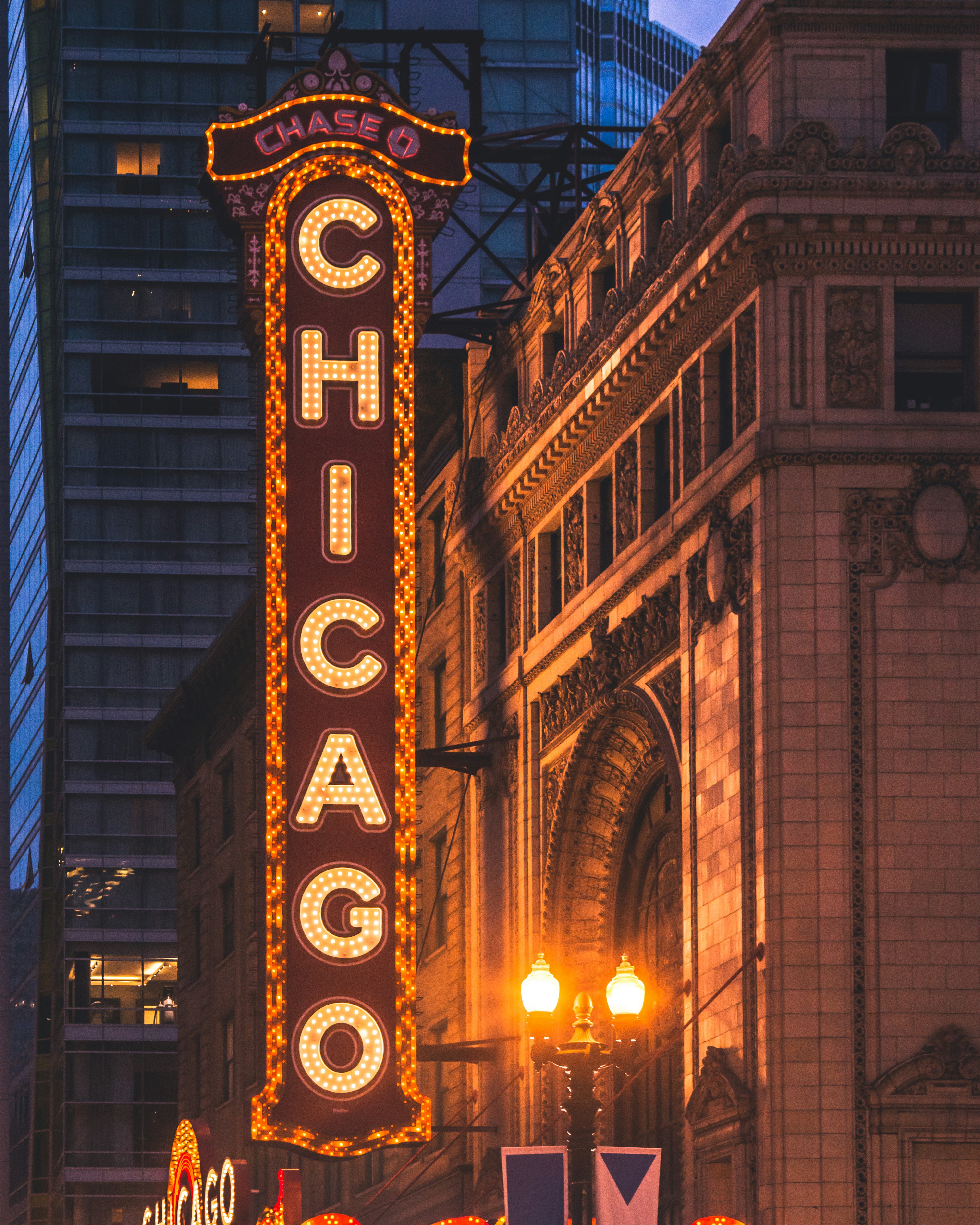 Illuminated 'CHICAGO' marquee sign in the theater district, showcasing vibrant neon lights against a backdrop of historic architecture.