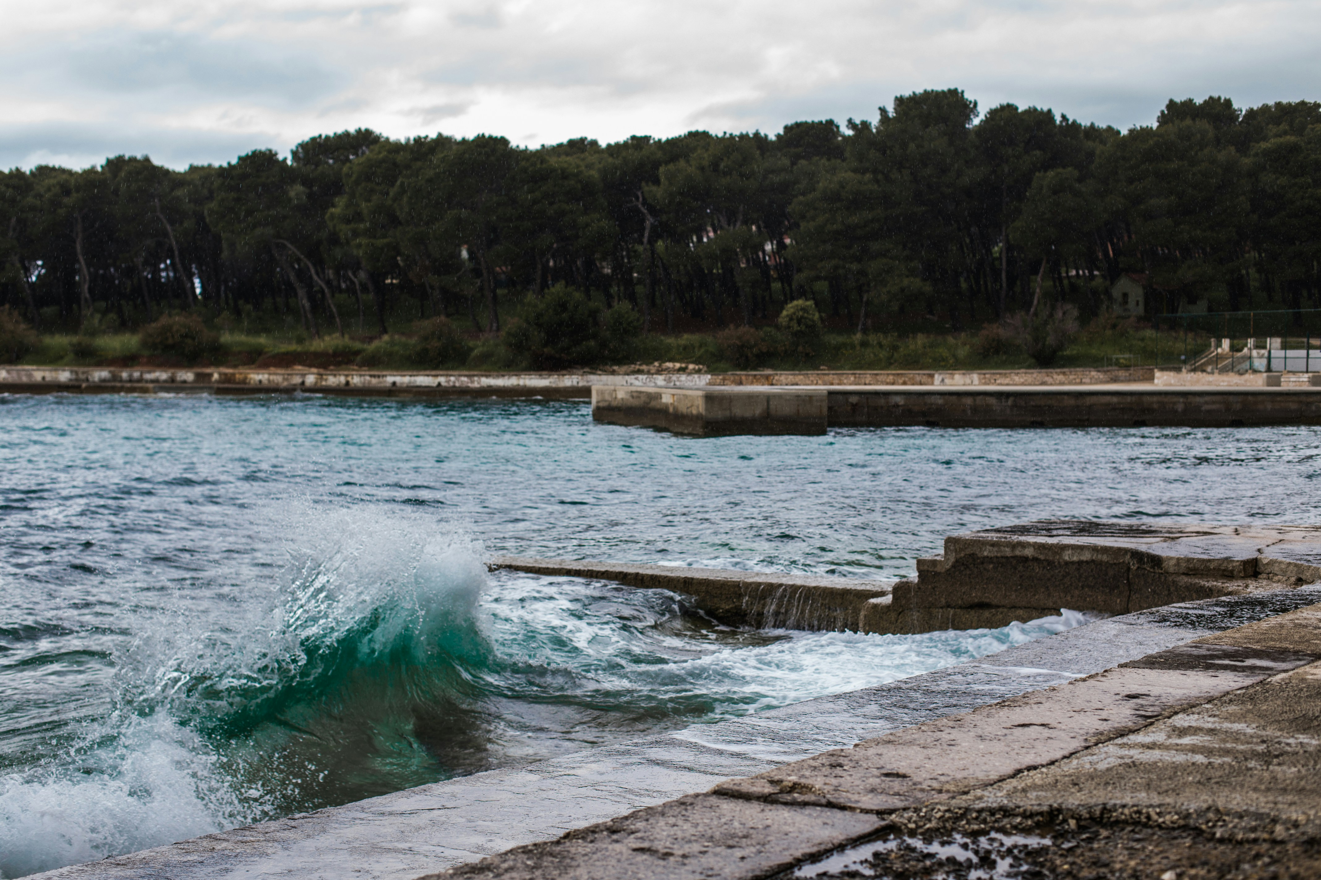 Verdant Breakwater Surge: A Turquoise Crest Leaps Against Weathered Jetty