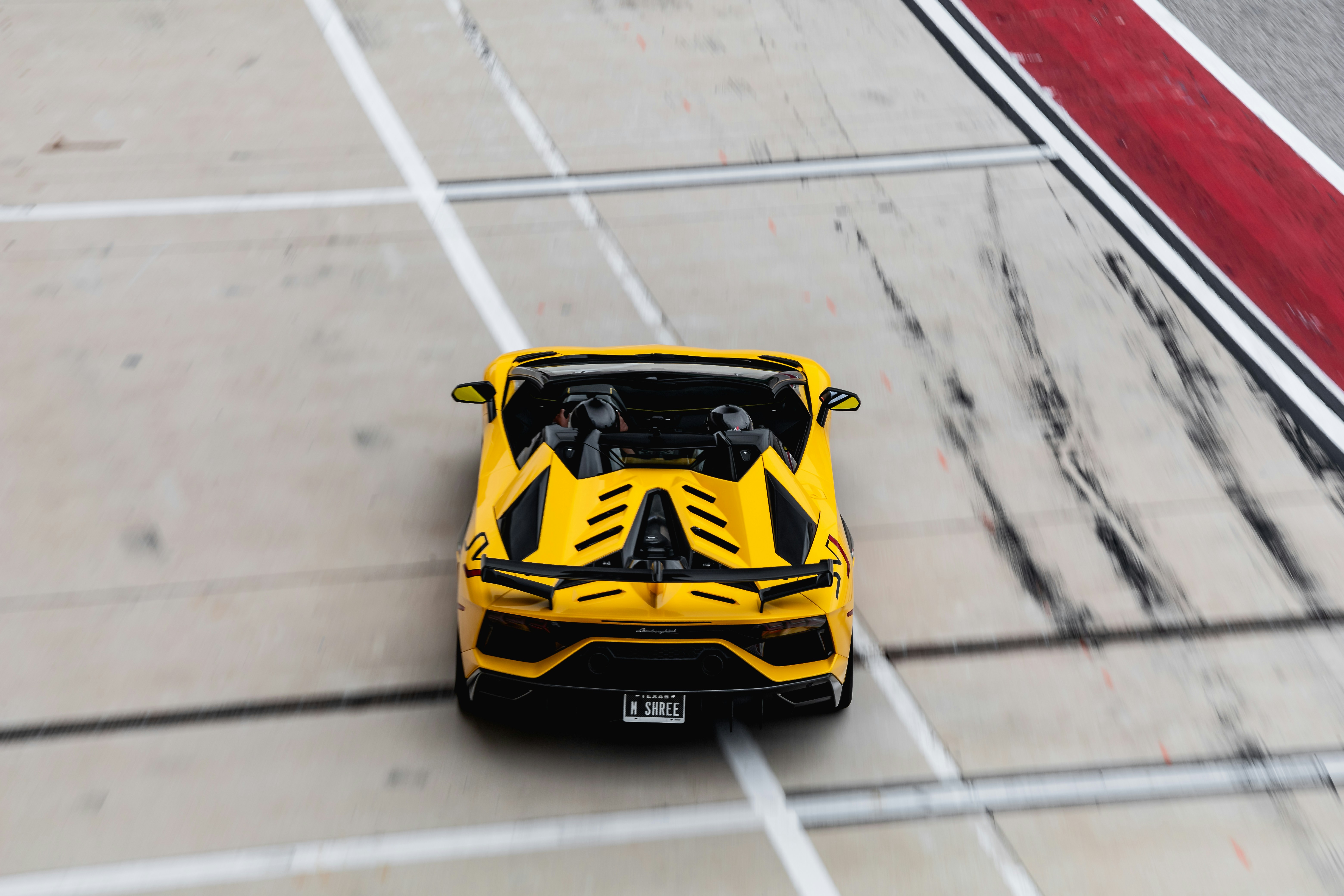 A sleek yellow sports car navigating a racetrack, showcasing its aerodynamic design and aggressive stance.