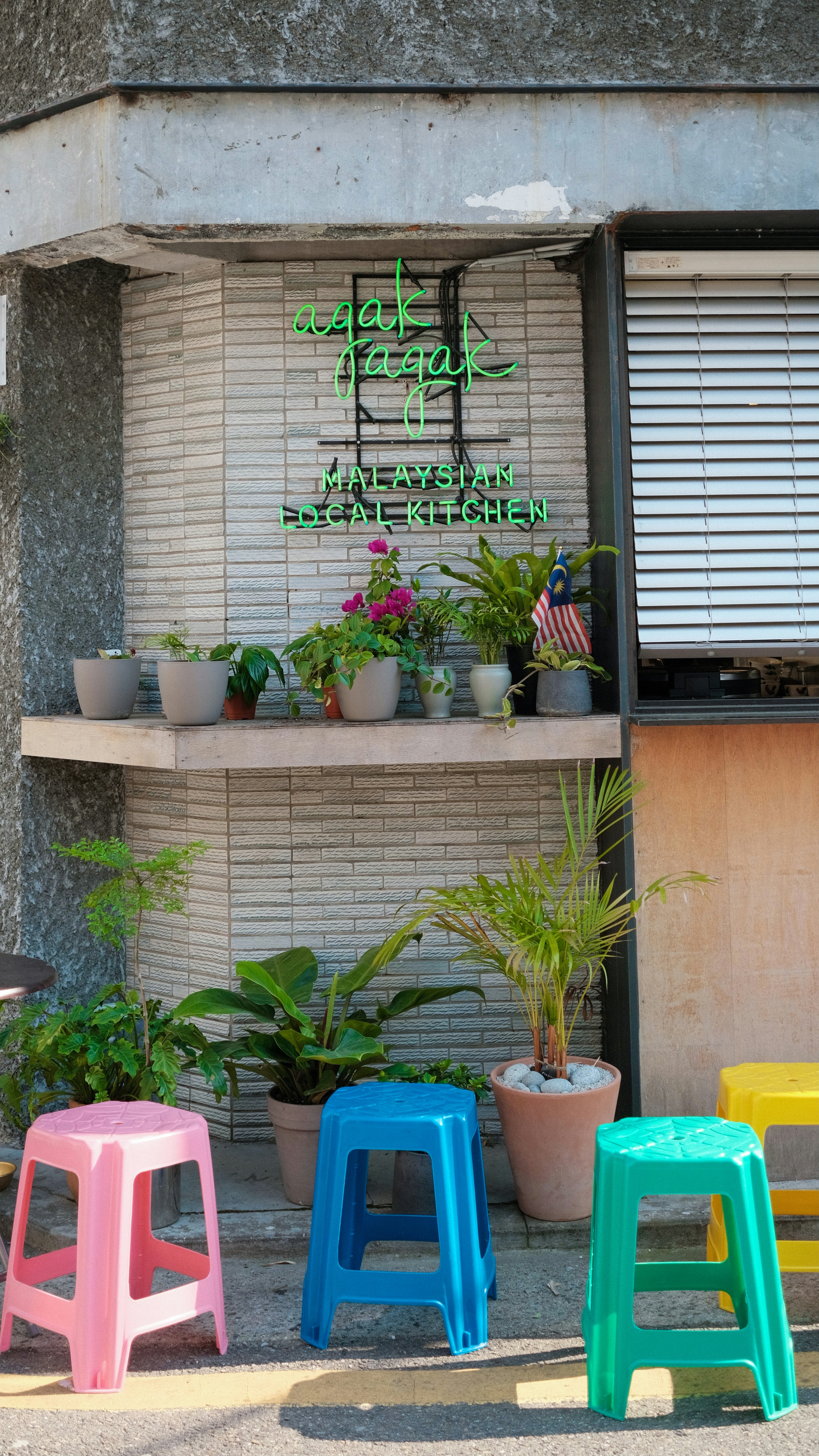 Colorful stools and neon sign mark a cozy Malaysian local kitchen
