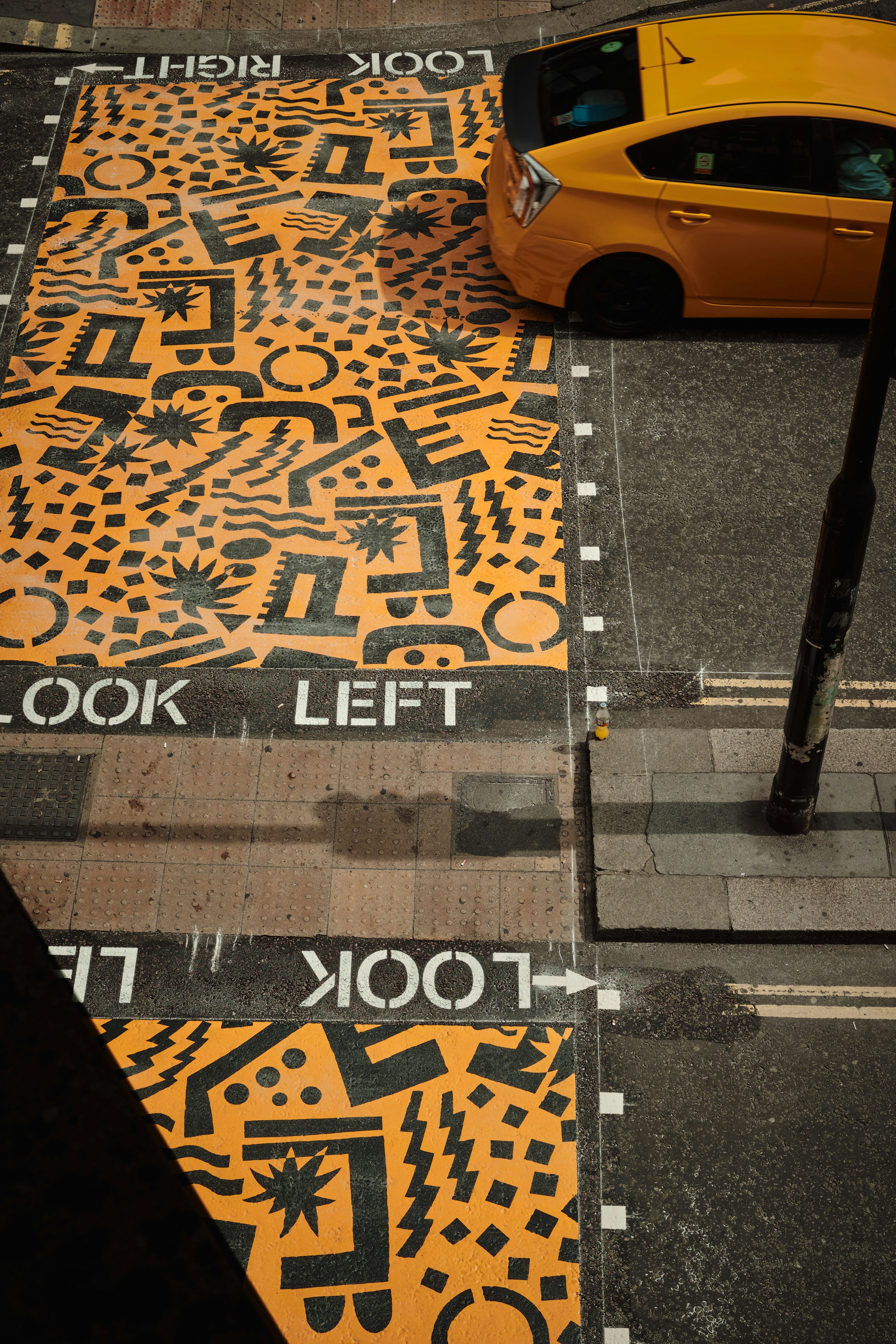 Yellow Taxi on a Geometric Crosswalk: City Rhythm in Orange and Black