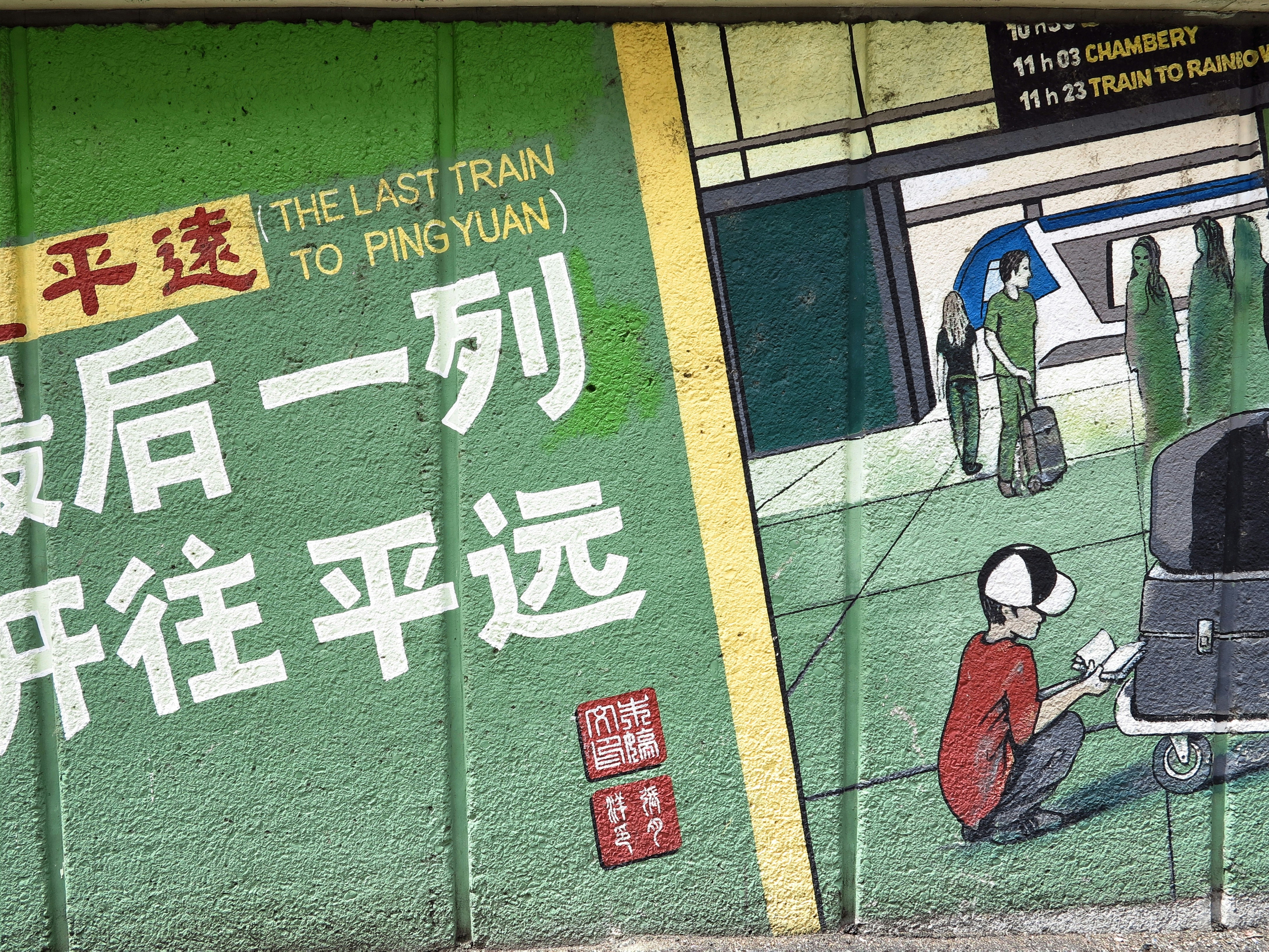 Mural painting of a station scene on a green wall, featuring a red-clad figure beside luggage and Chinese characters with The Last Train to Pingyuan.