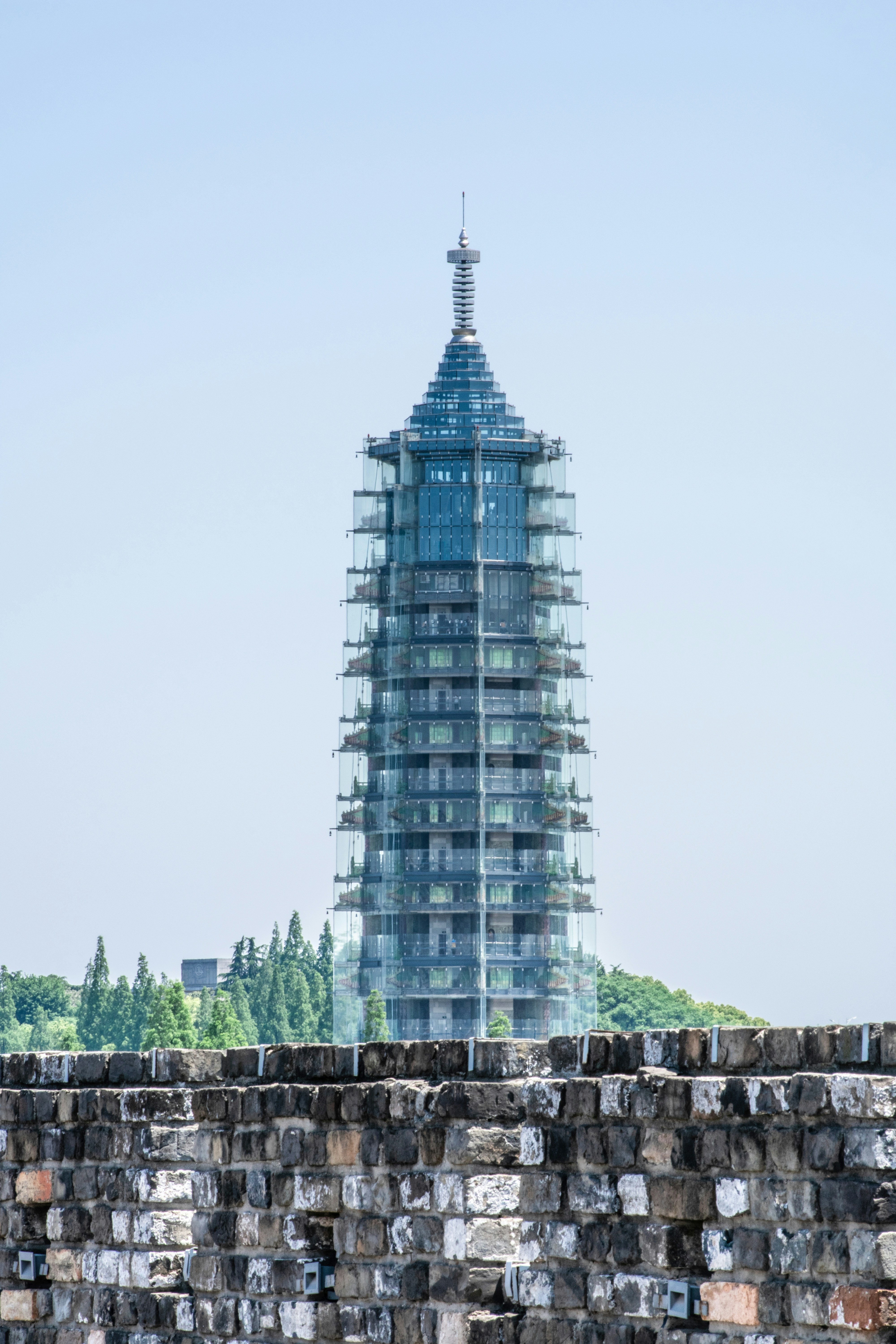 Looming Glass Tower Under Construction Behind a Weathered Stone Wall