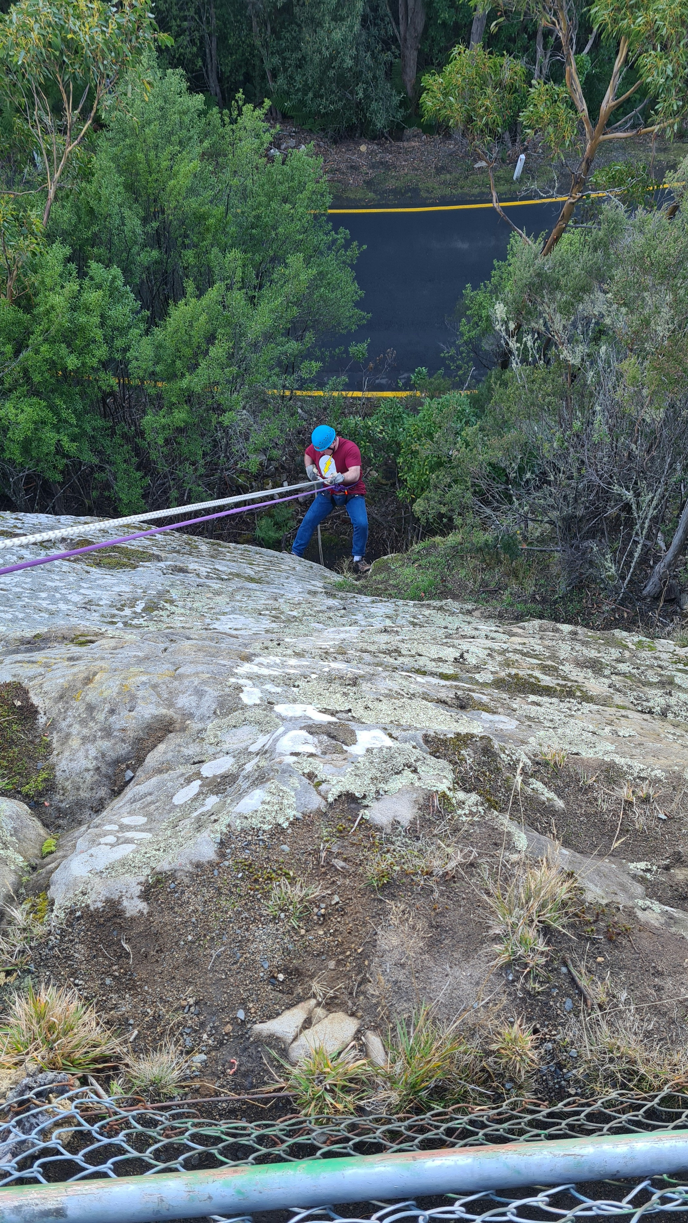 man in red and blue jacket and black pants walking on rocky mountain during daytime