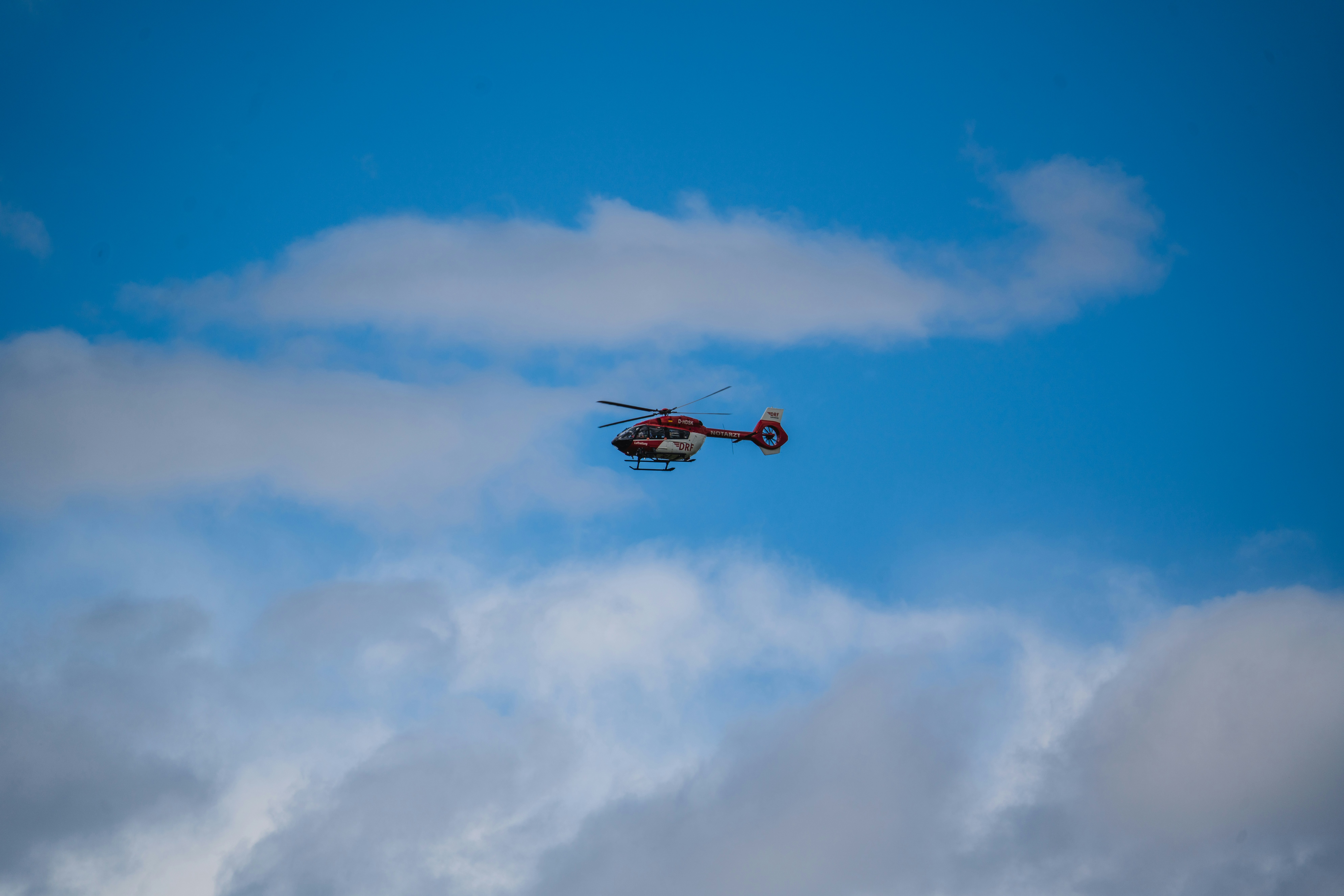 red and black helicopter flying in the sky