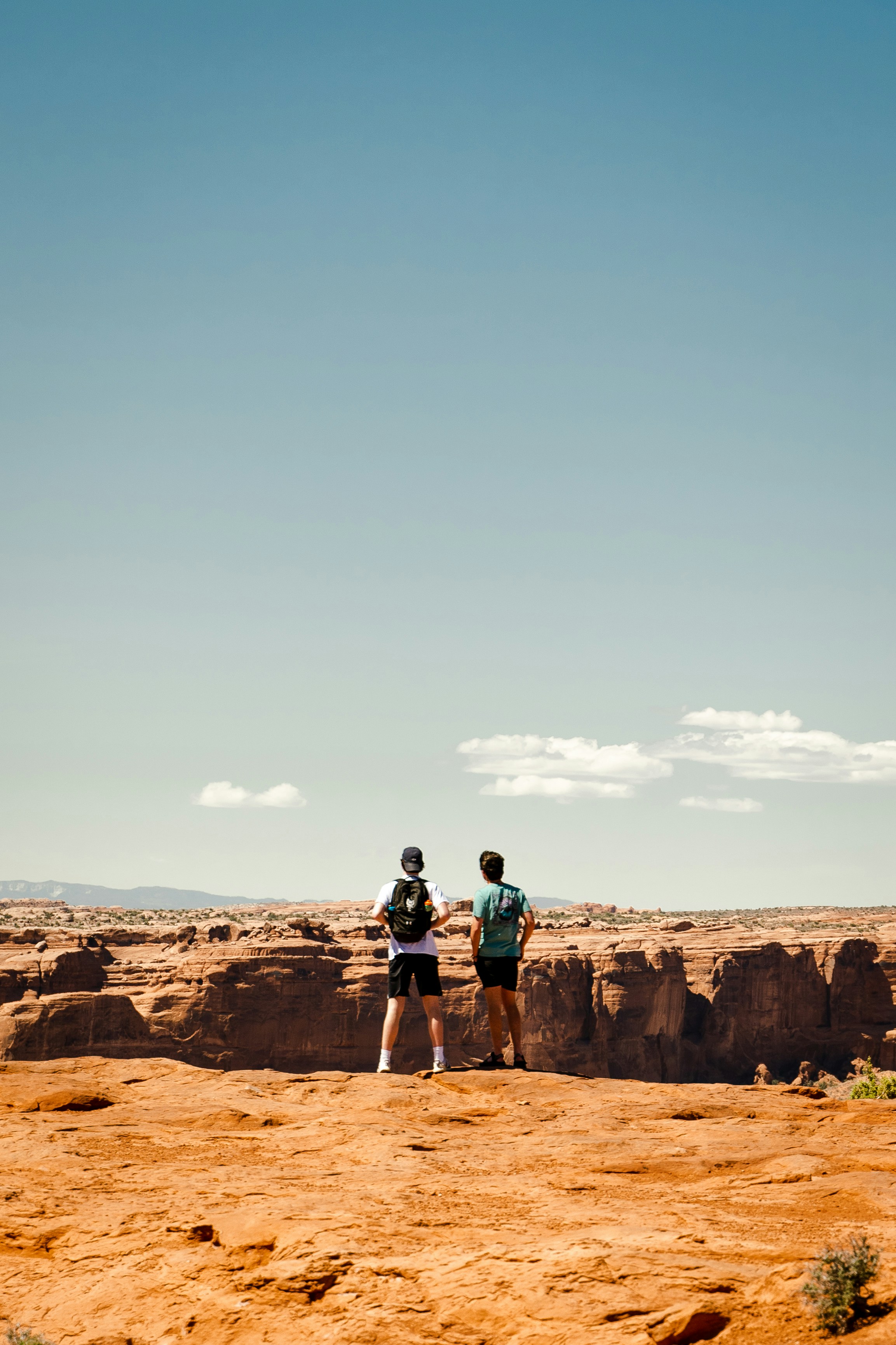 Rim View: Two hikers on the edge of a desert canyon under a vast sky