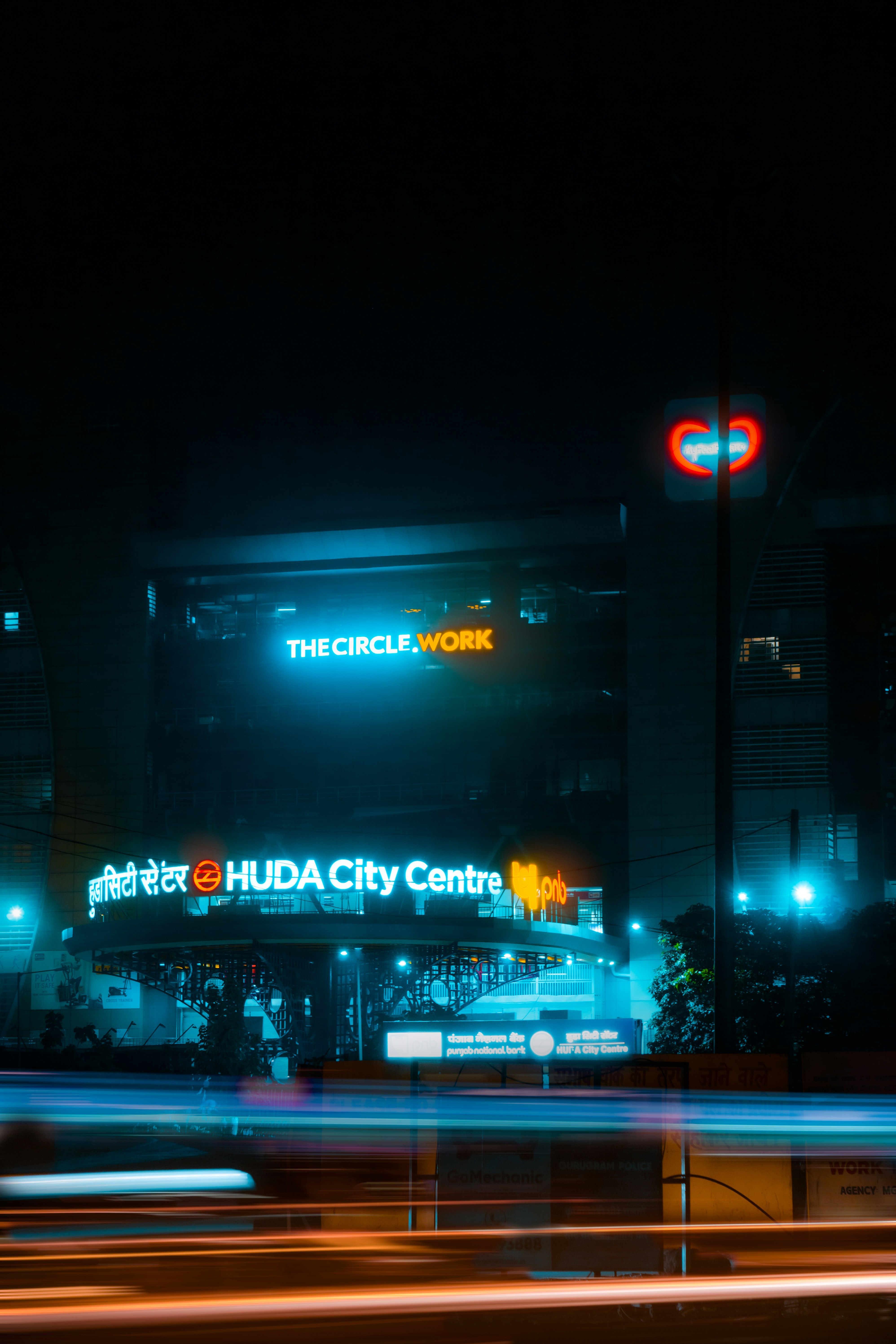 Illuminated HUDA City Centre signage at night, showcasing vibrant neon lights and dynamic urban movement.
