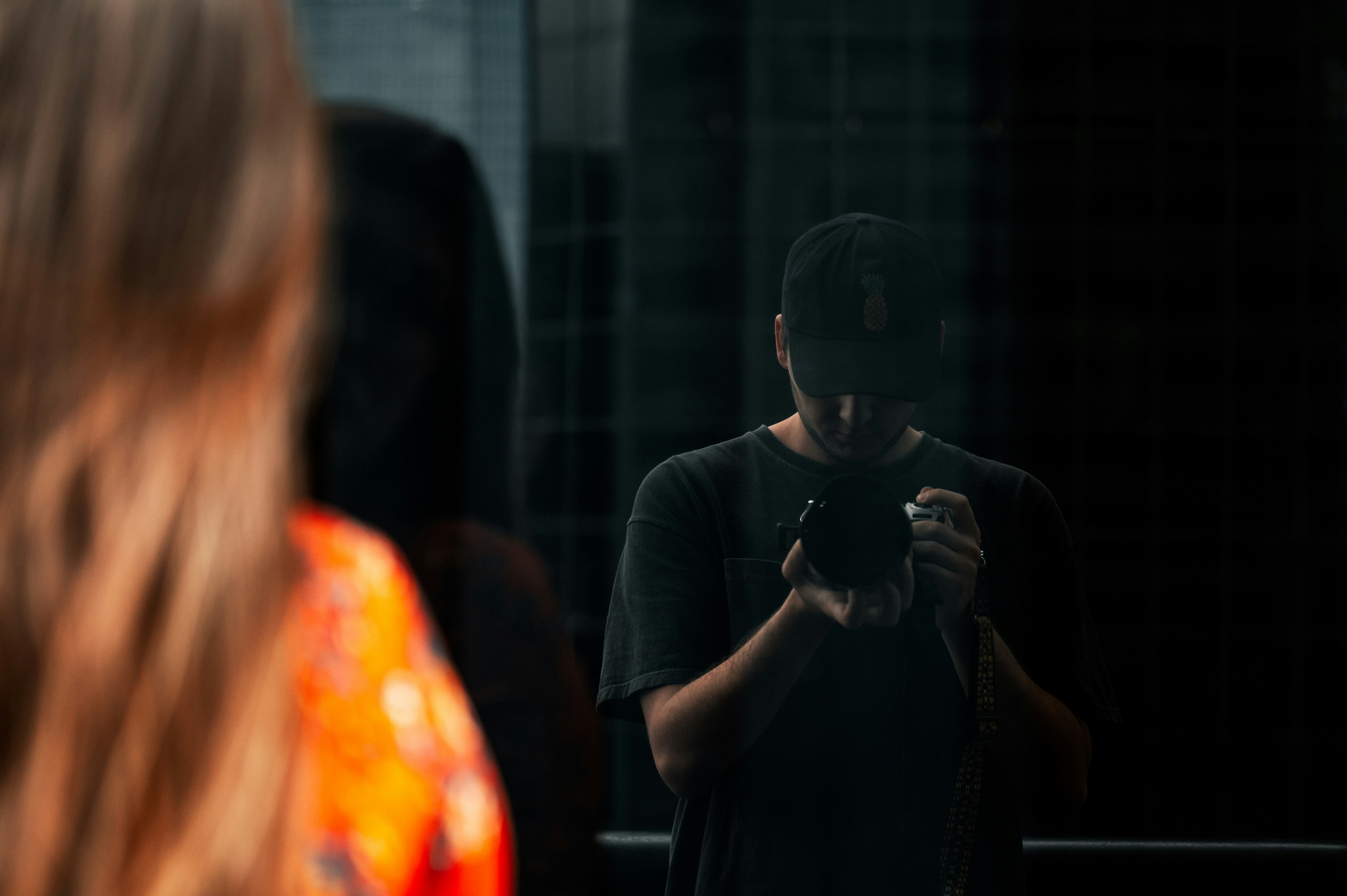 A photographer capturing a moment, reflected in a sleek glass surface, with a vibrant figure in the foreground.