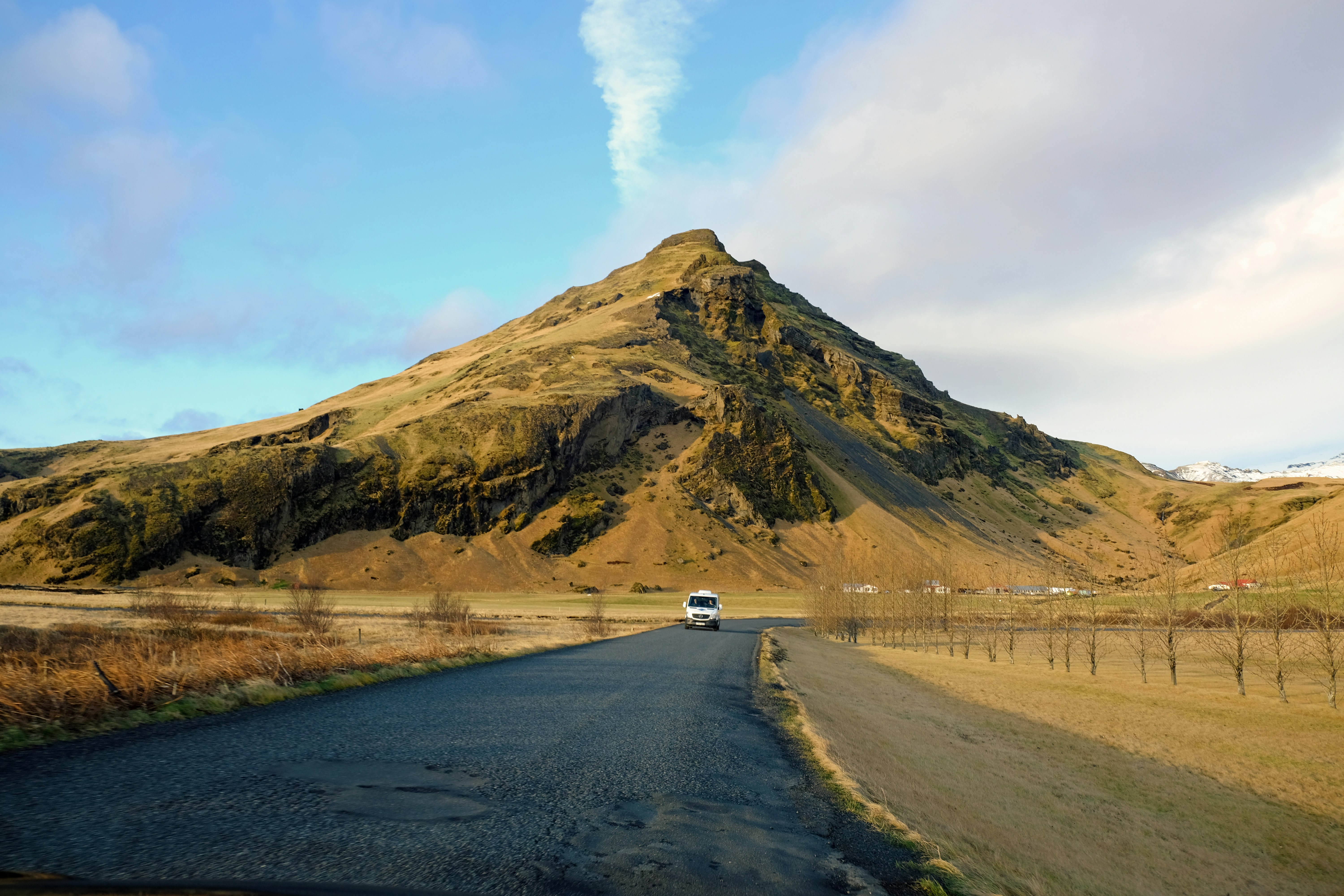Road to the Peak: A Lone Car Beneath a Rugged Summit