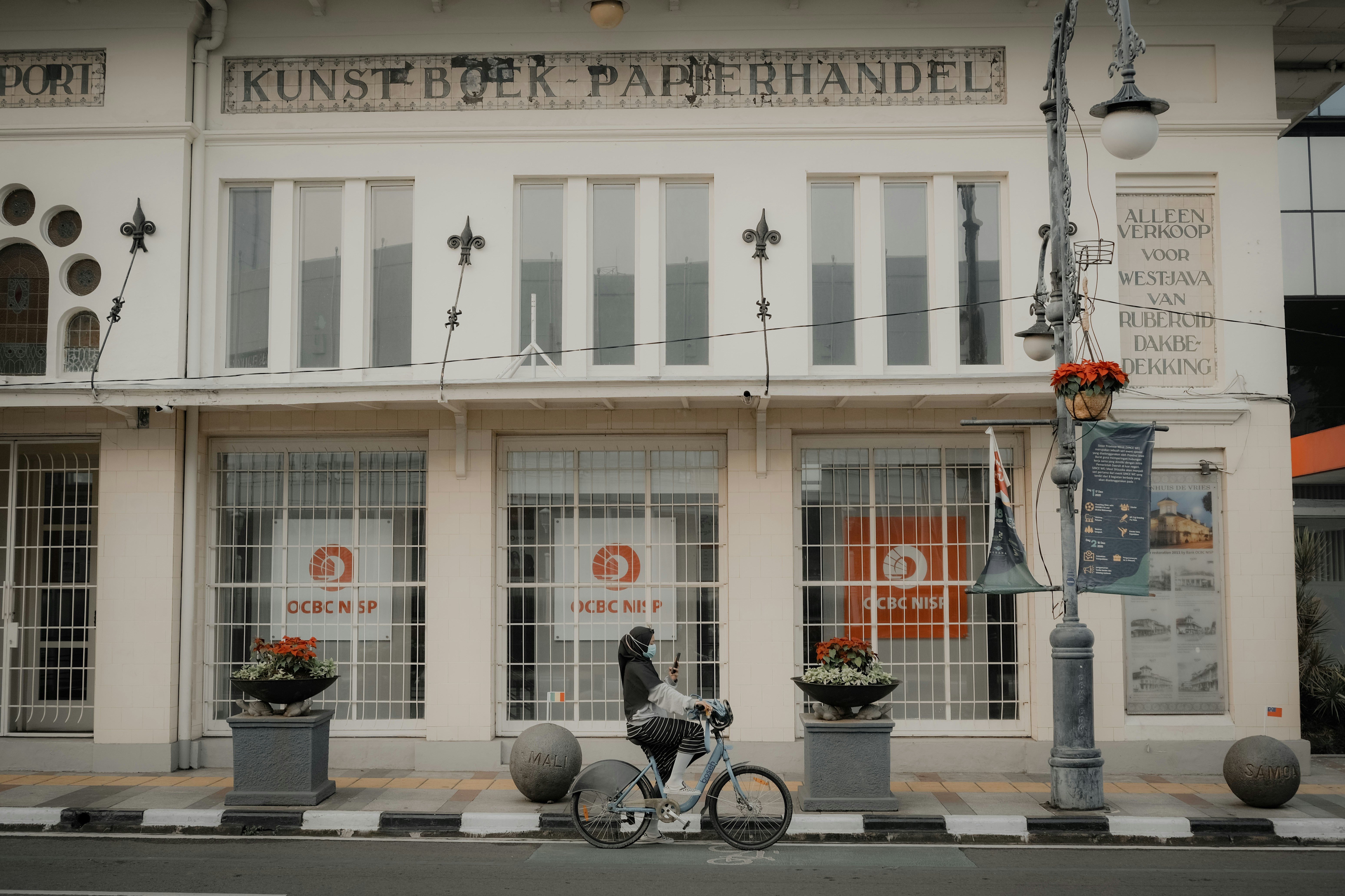 man in black jacket riding on bicycle in front of white concrete building during daytime